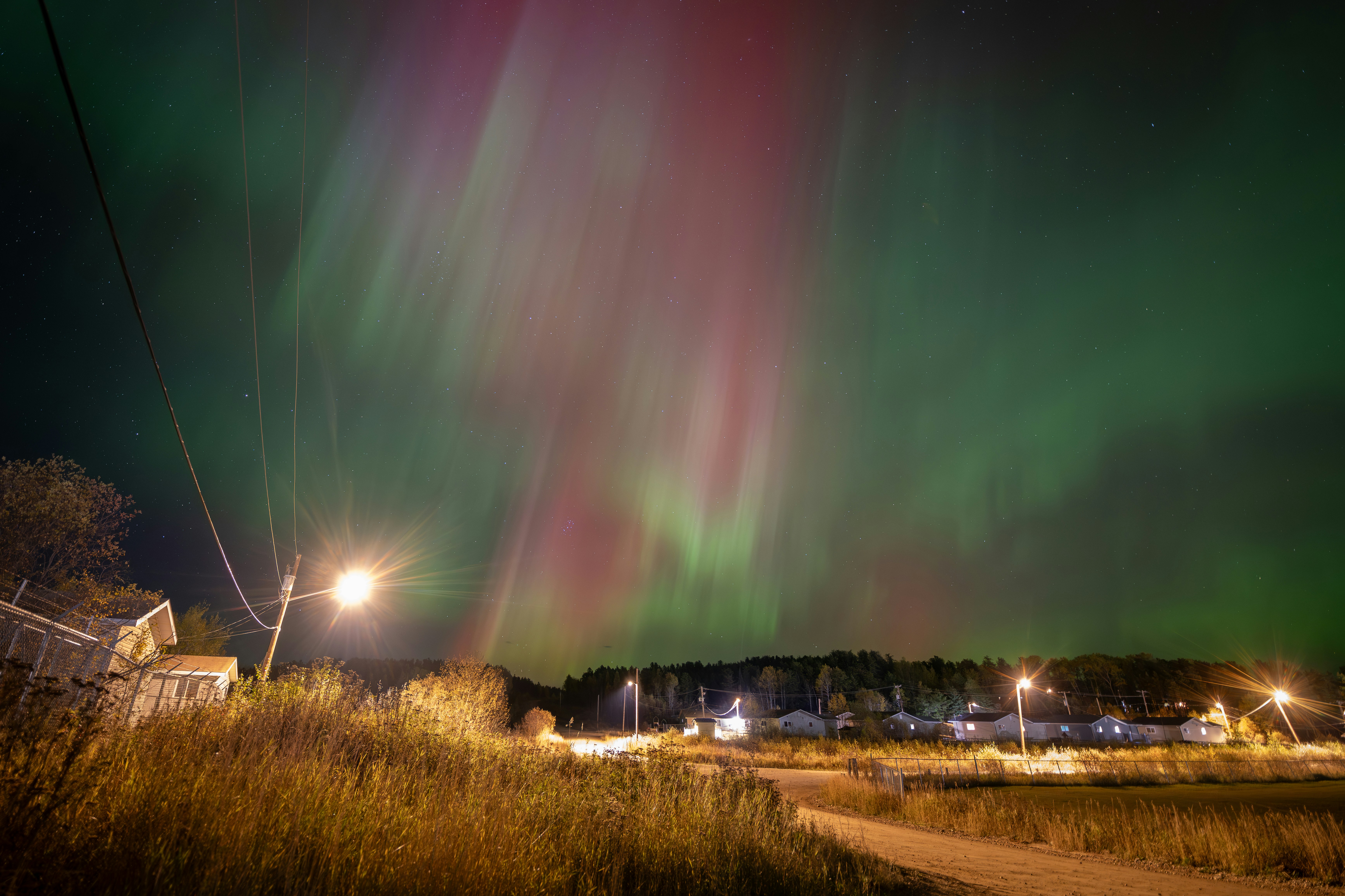 Aurora Over Static Street: Night Sky Painted in Green and Pink