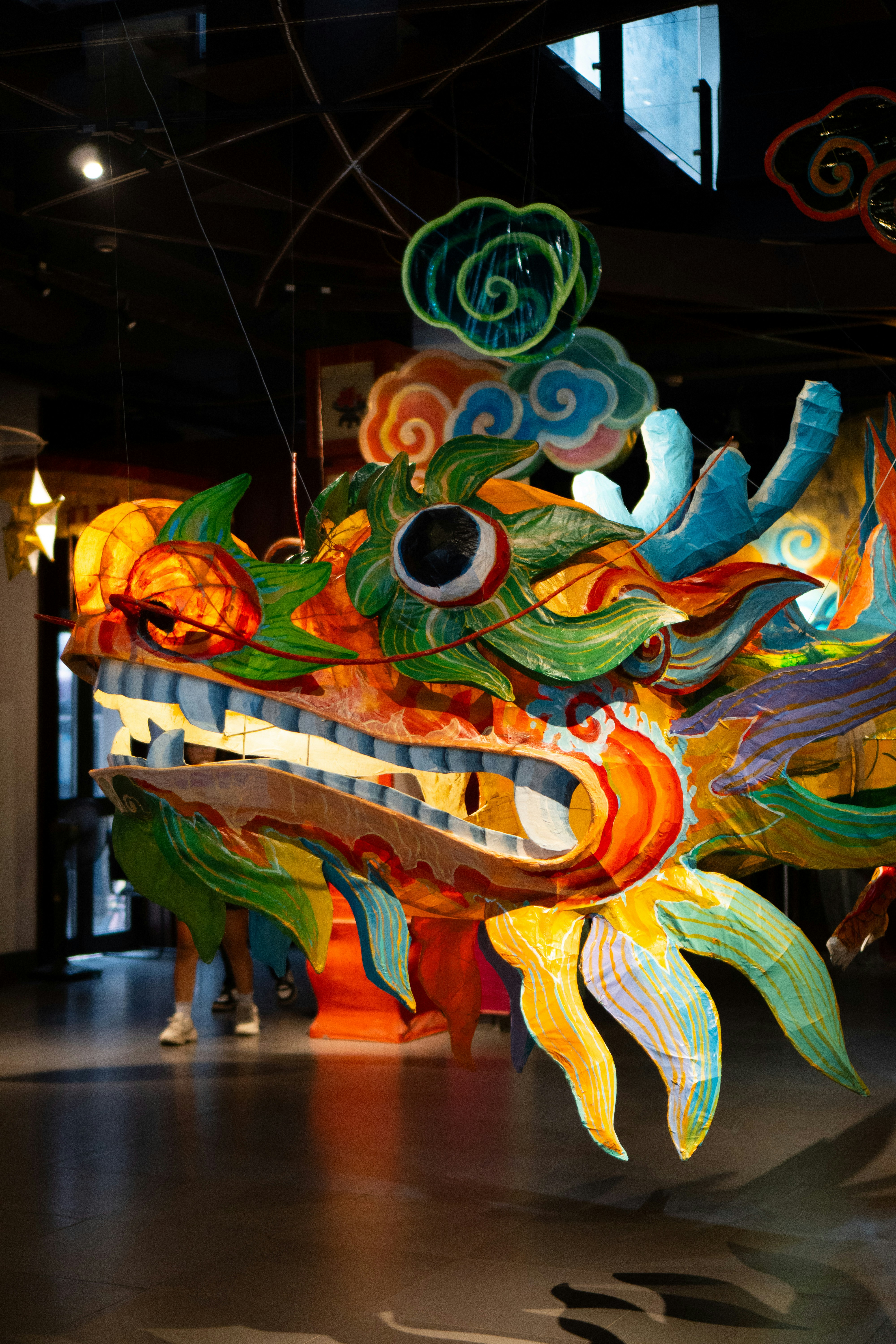 Dragon's Gleam: A kaleidoscopic sculpture suspended in shadowed gallery light