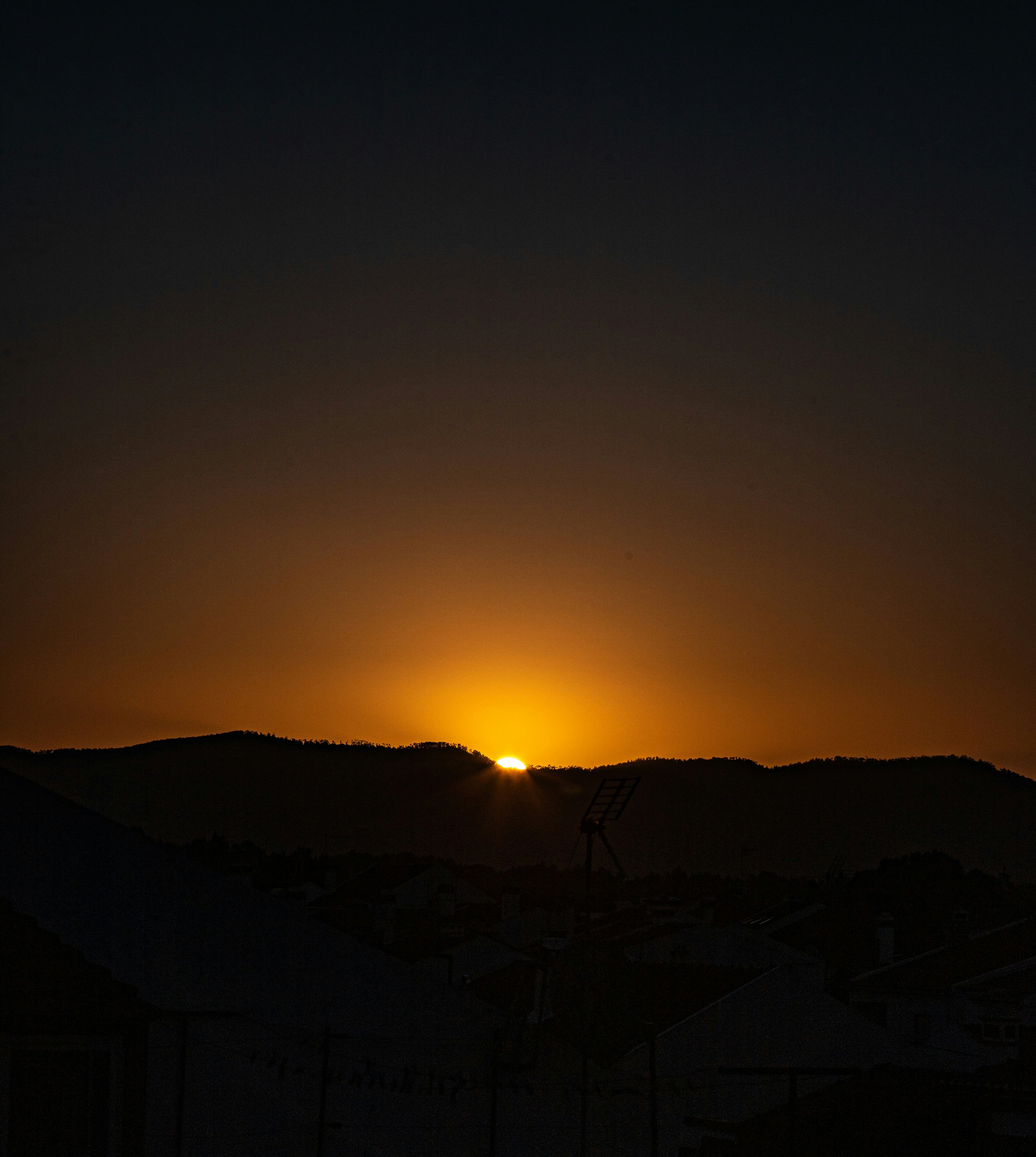 Sunset Crest Over Quiet Ridge with Rooftop Silhouette