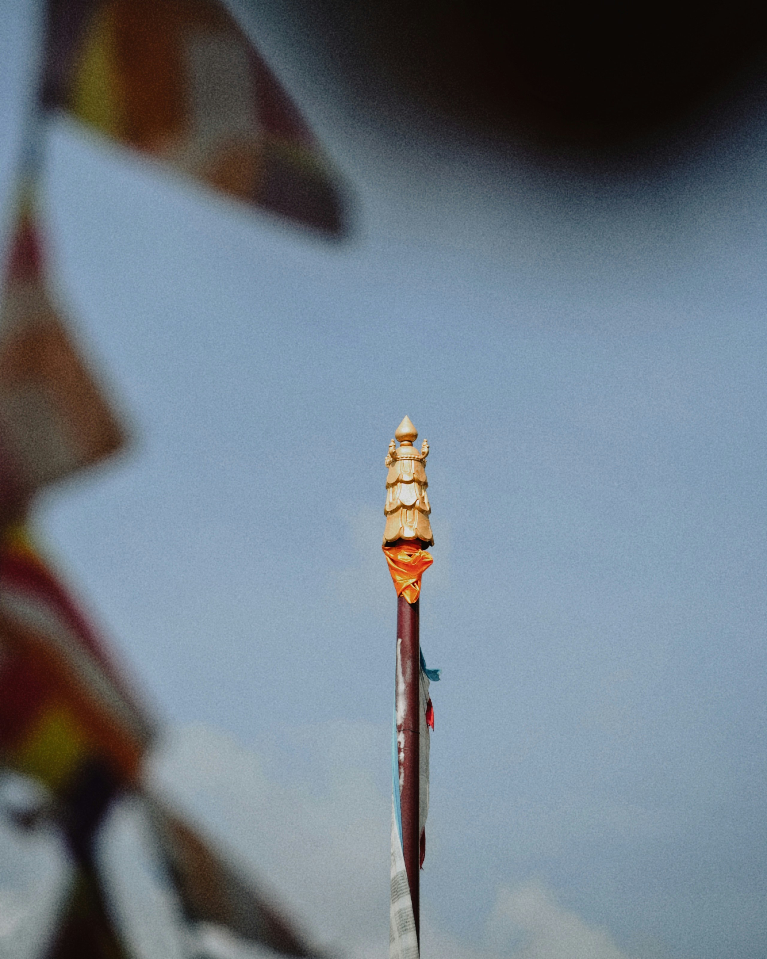 Topped Standard: A Prayer Flag Enshrined Spire against a Clear Sky