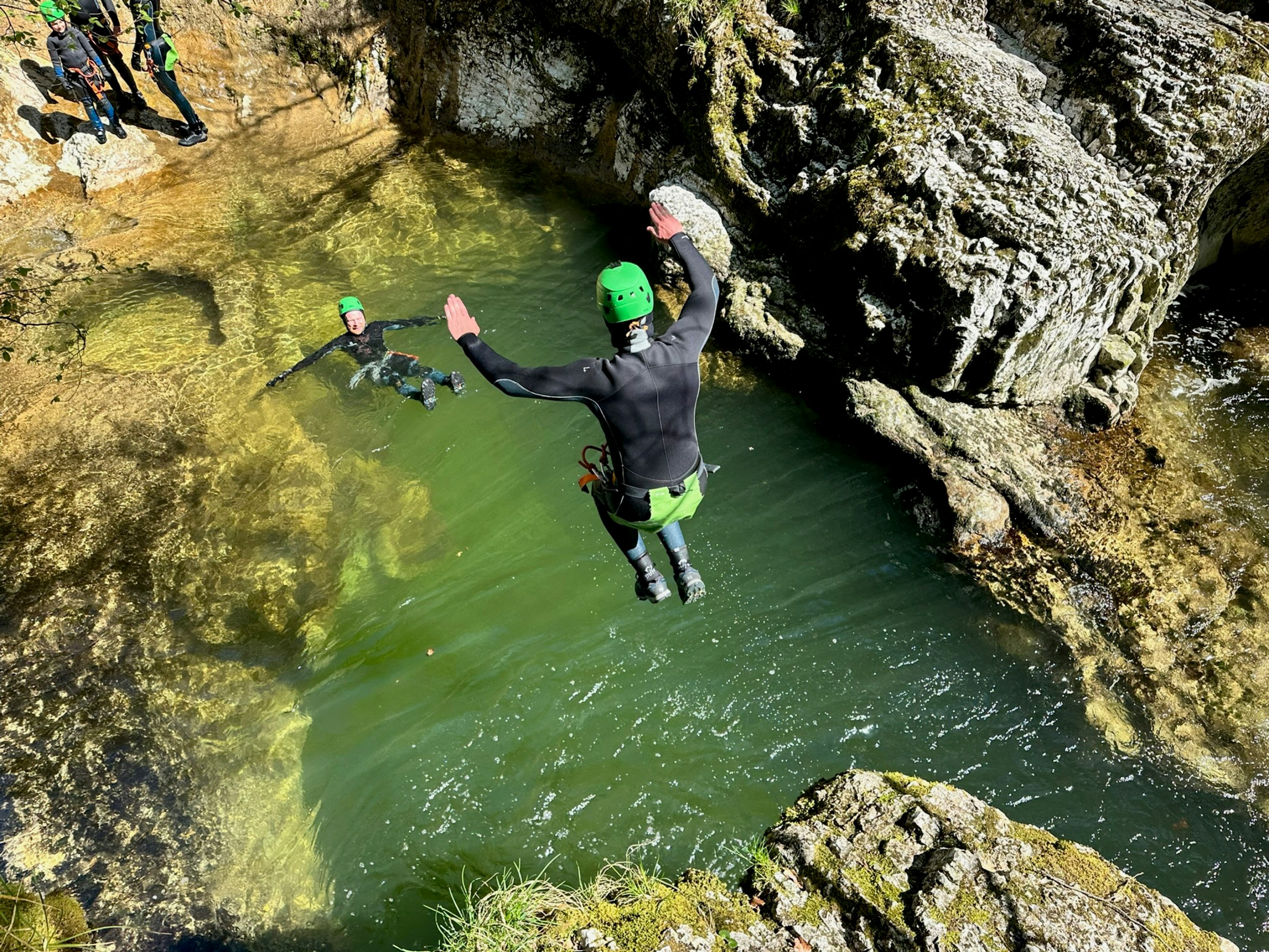 Canyon plunge: climbers drop into emerald water from rugged rock