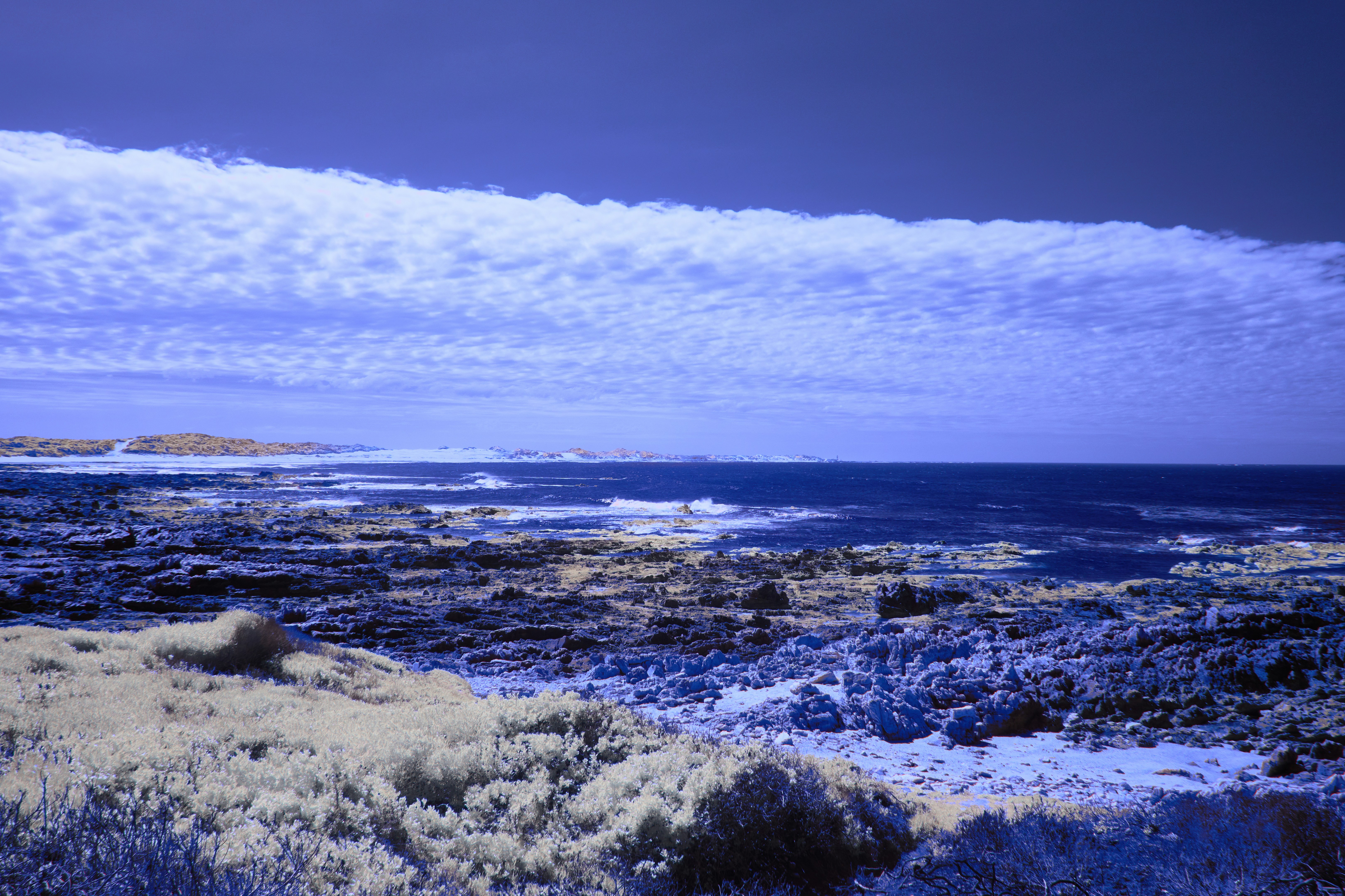 Coastal Mirage: Blue Hues Over Tidal Rocks