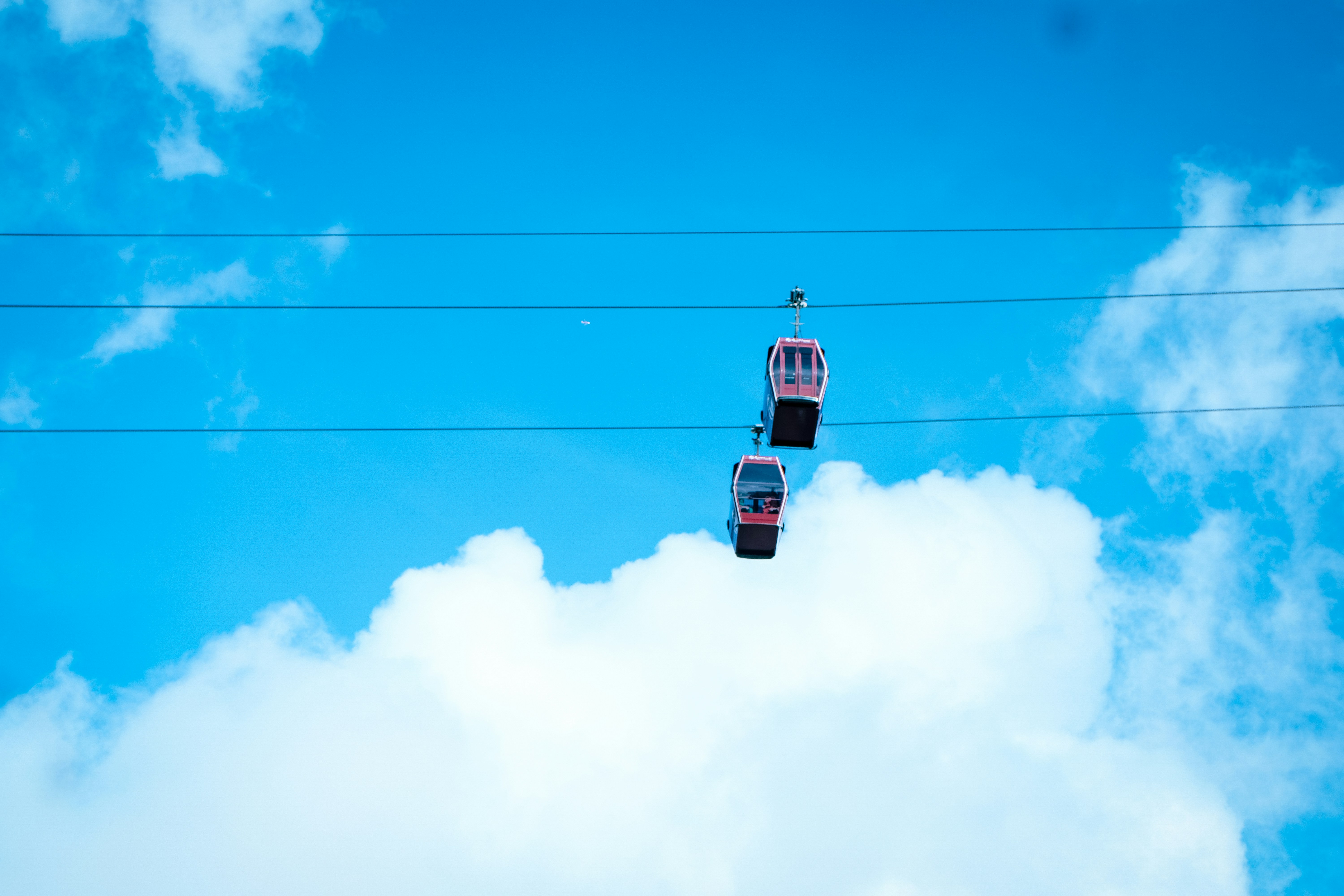 Suspended in Blue: Twin Cable Cars Crossing a Sky of Clouds