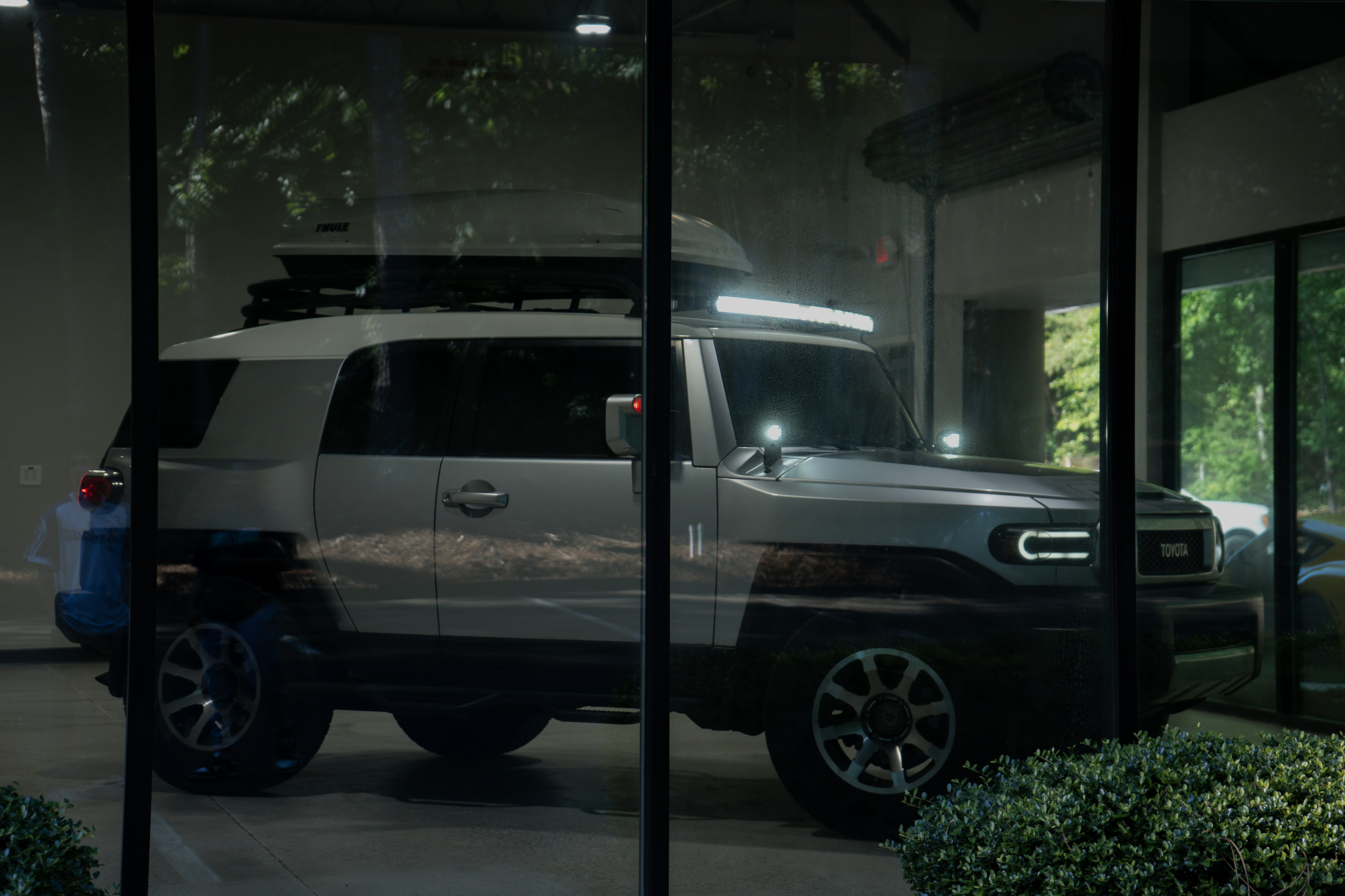 Reflection of a rugged SUV in glass: hidden details in a showroom silhouette