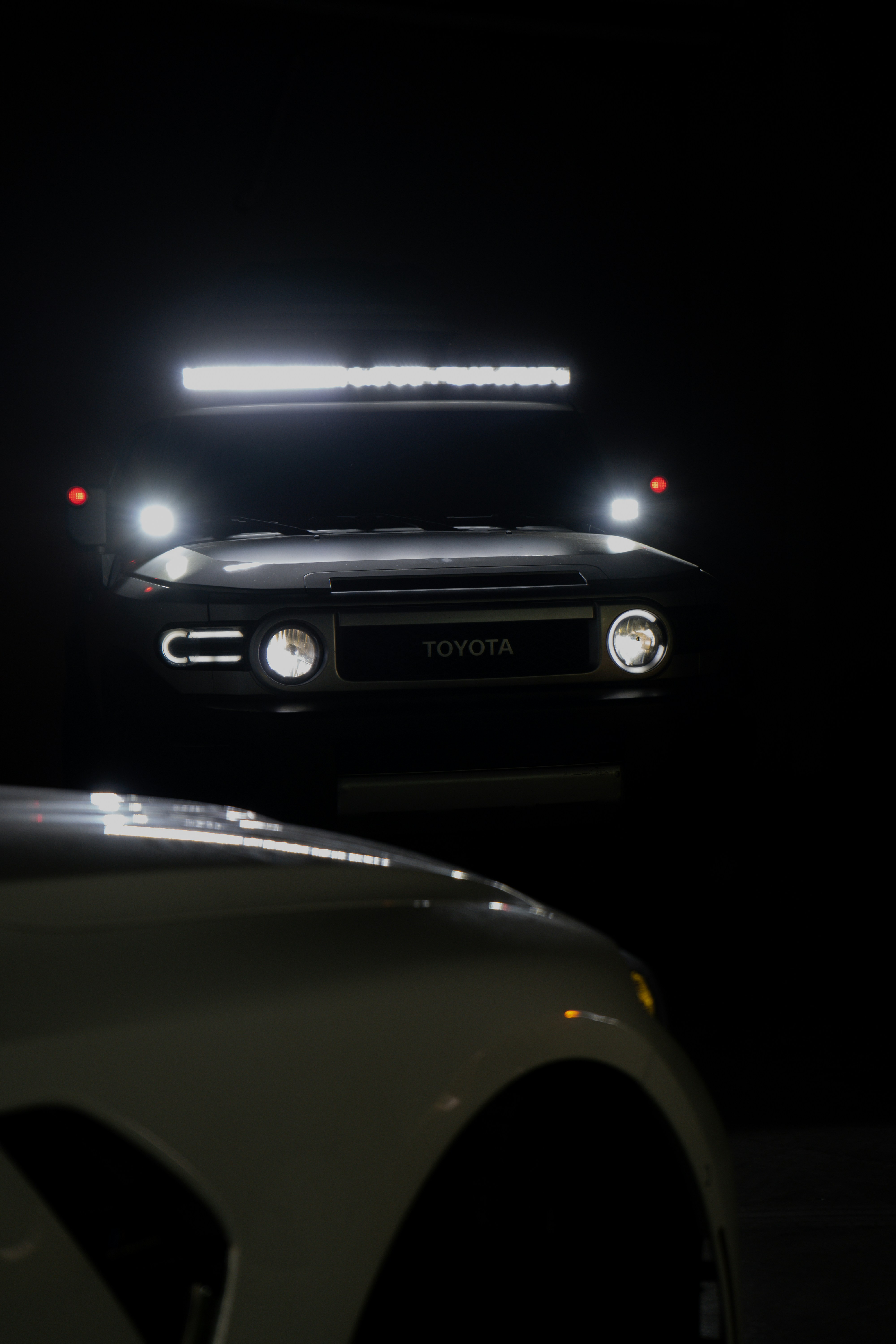 Low-Light Toyota Grit: A Nighttime Front-View with Bright Roof Bar
