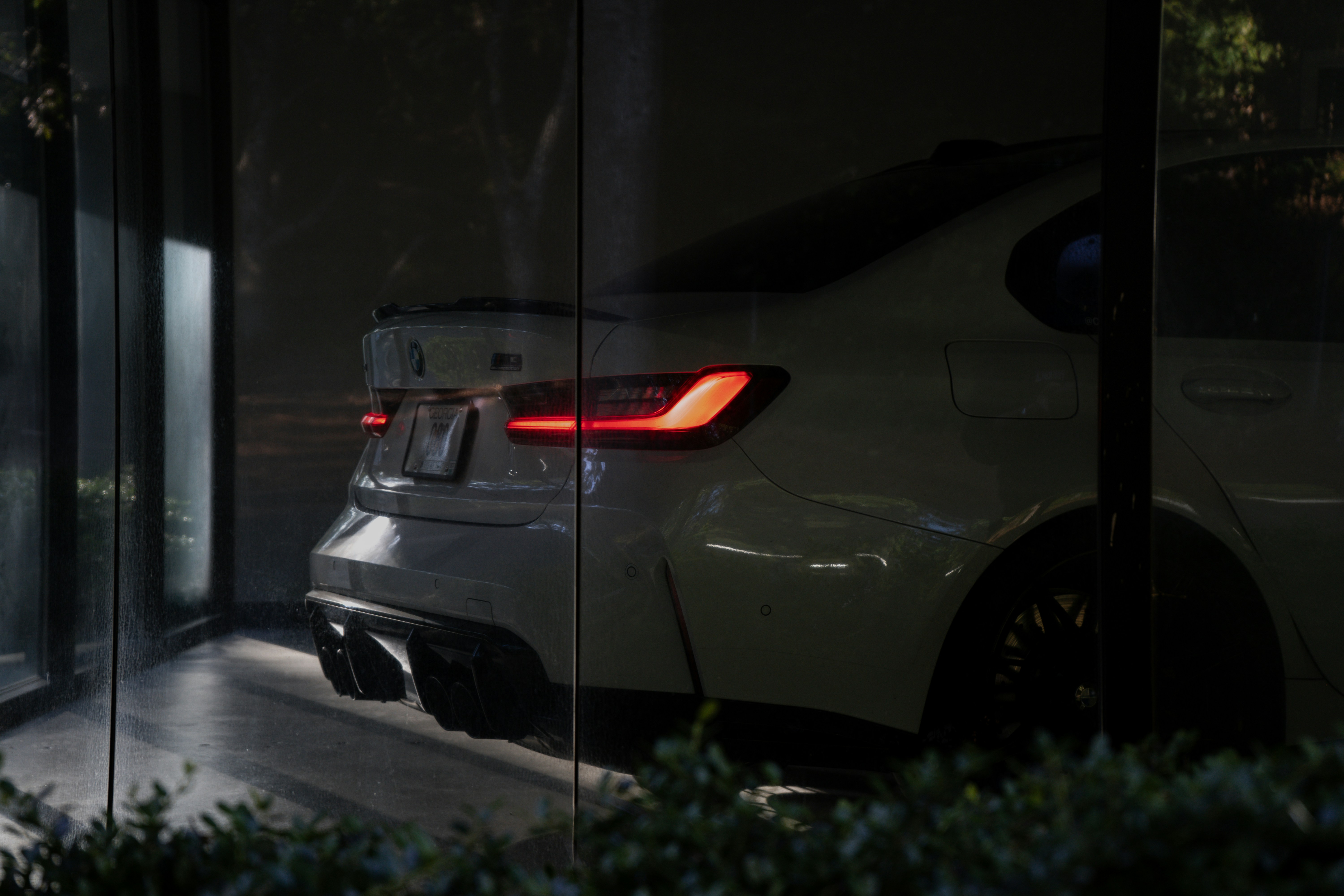Hidden Luxury: A White Sedan Reflected in a Glass-Front Gallery