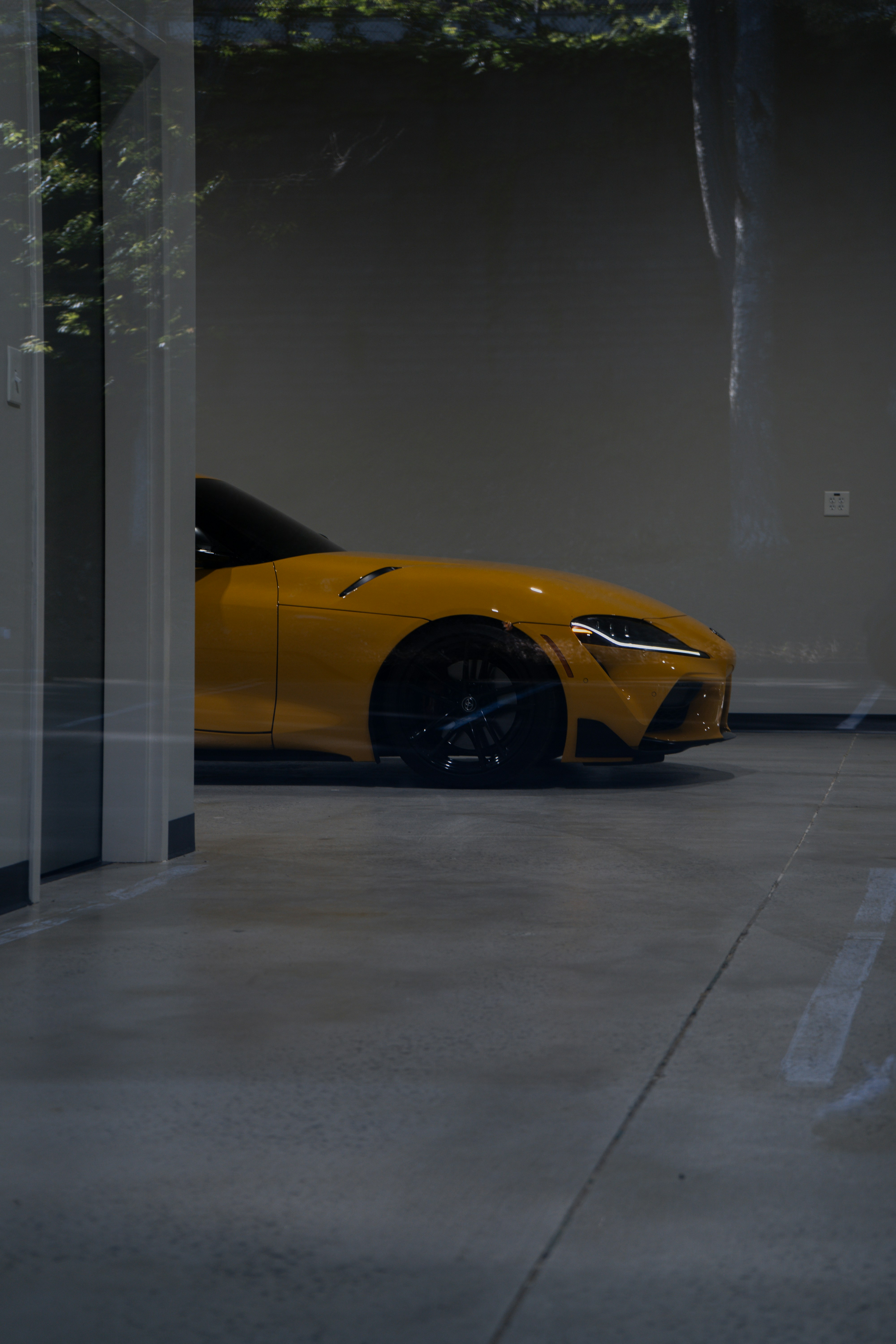 Yellow supercar emerging from a dim showroom halo