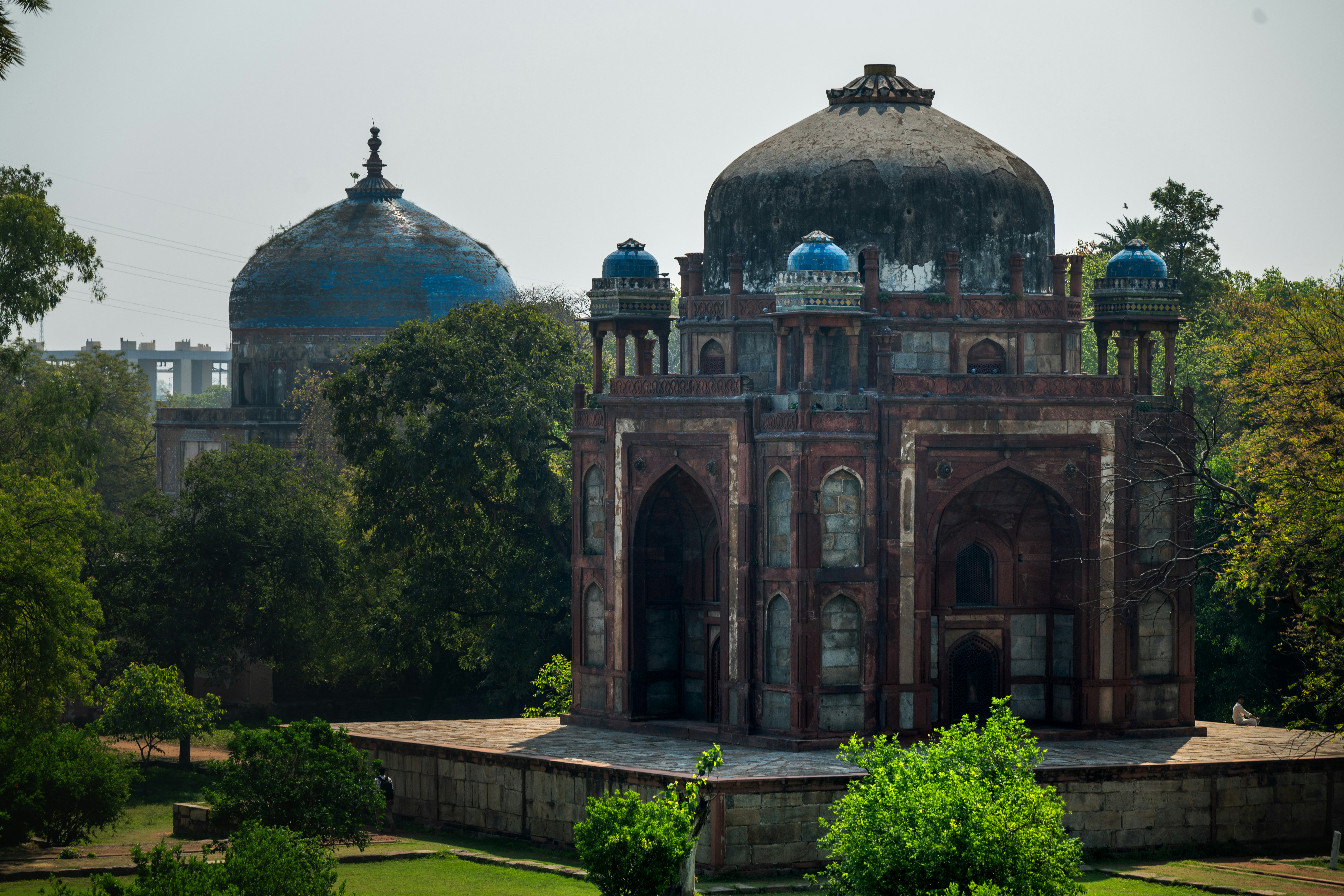 Ancient Gatehouse of Delhi: Weathered Domes and Lush Grounds