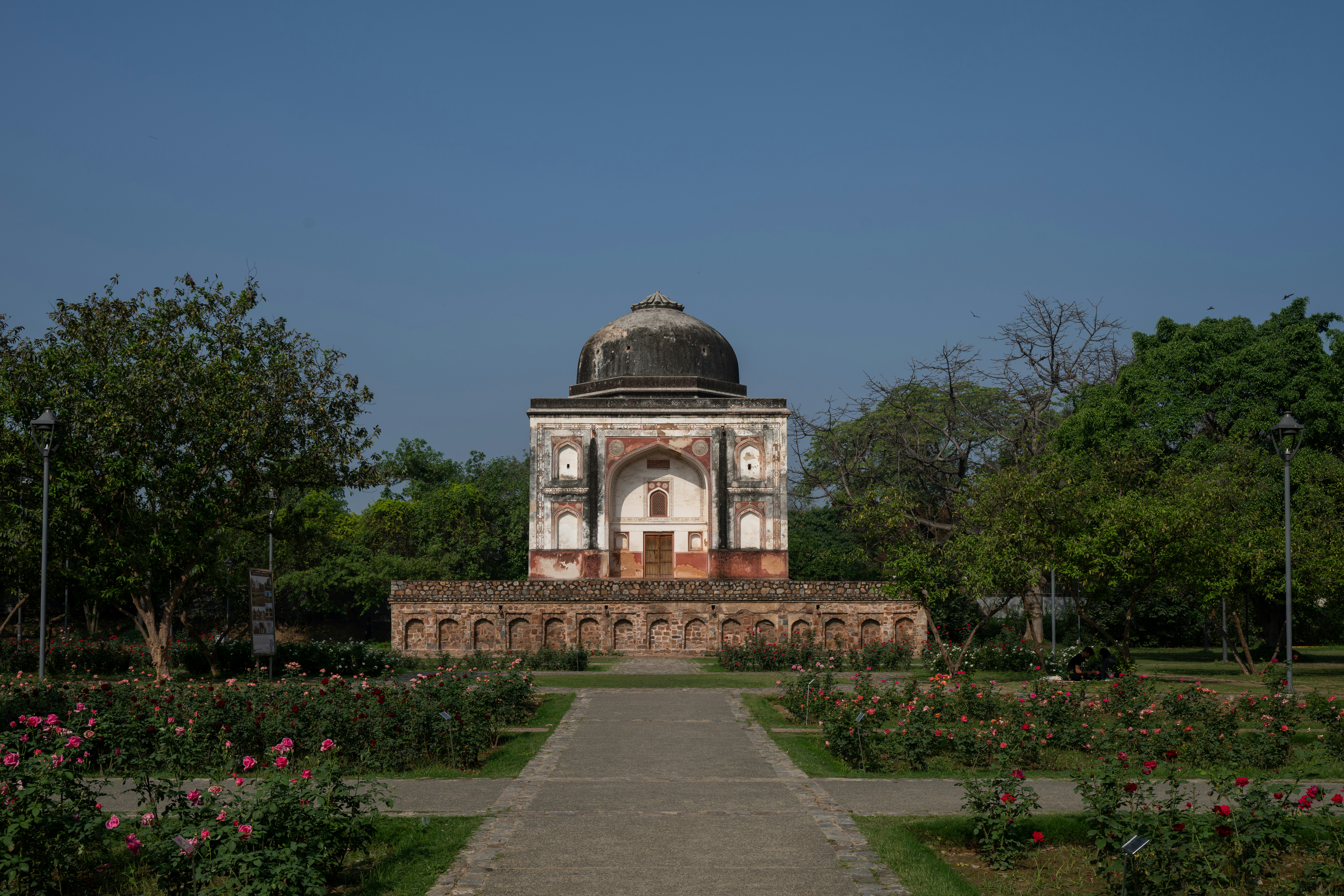 Ancient domed tomb in a serene garden with a path.