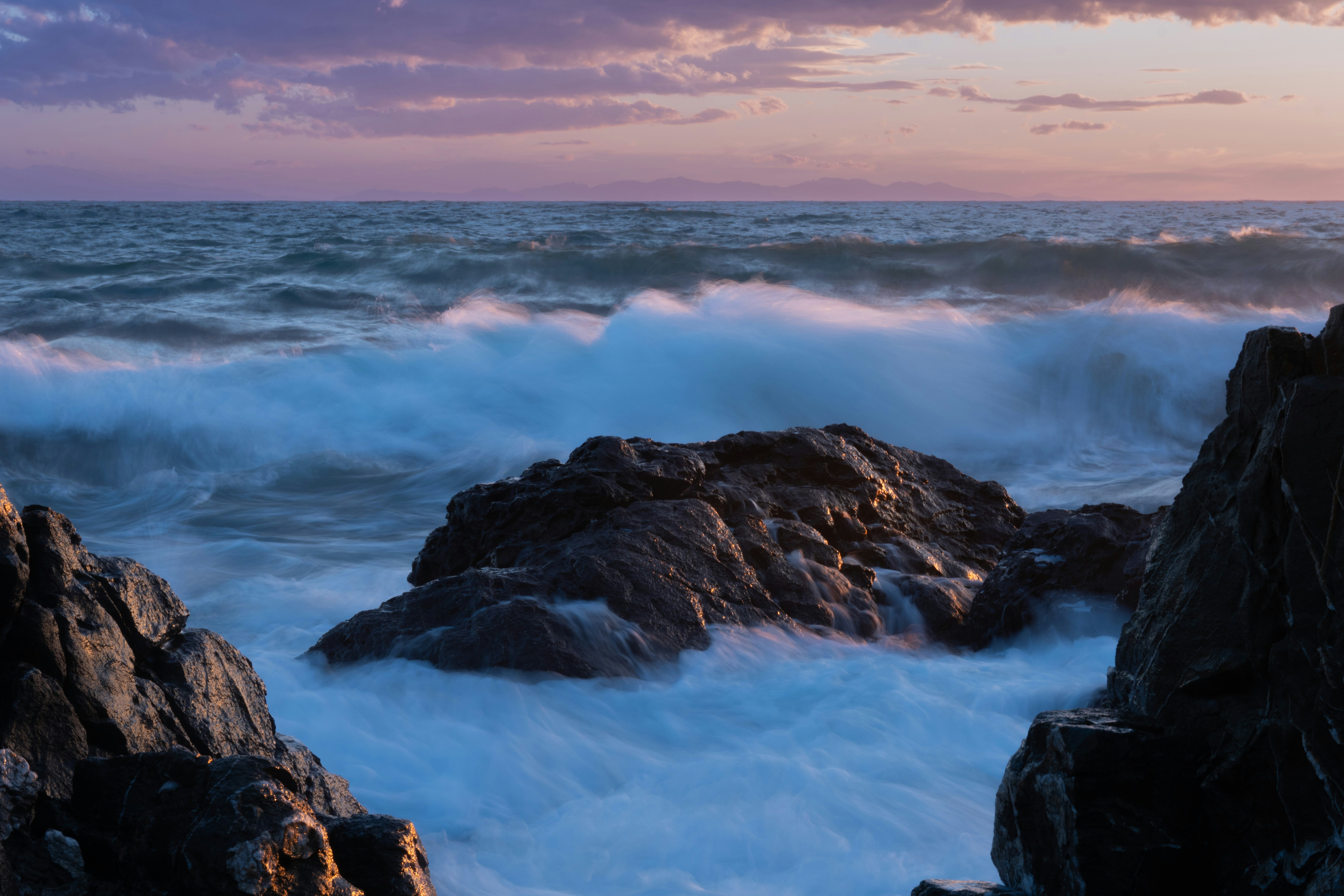 Sunlit Break: Rugged Rocks Meet a Velvet Sea at Dusk
