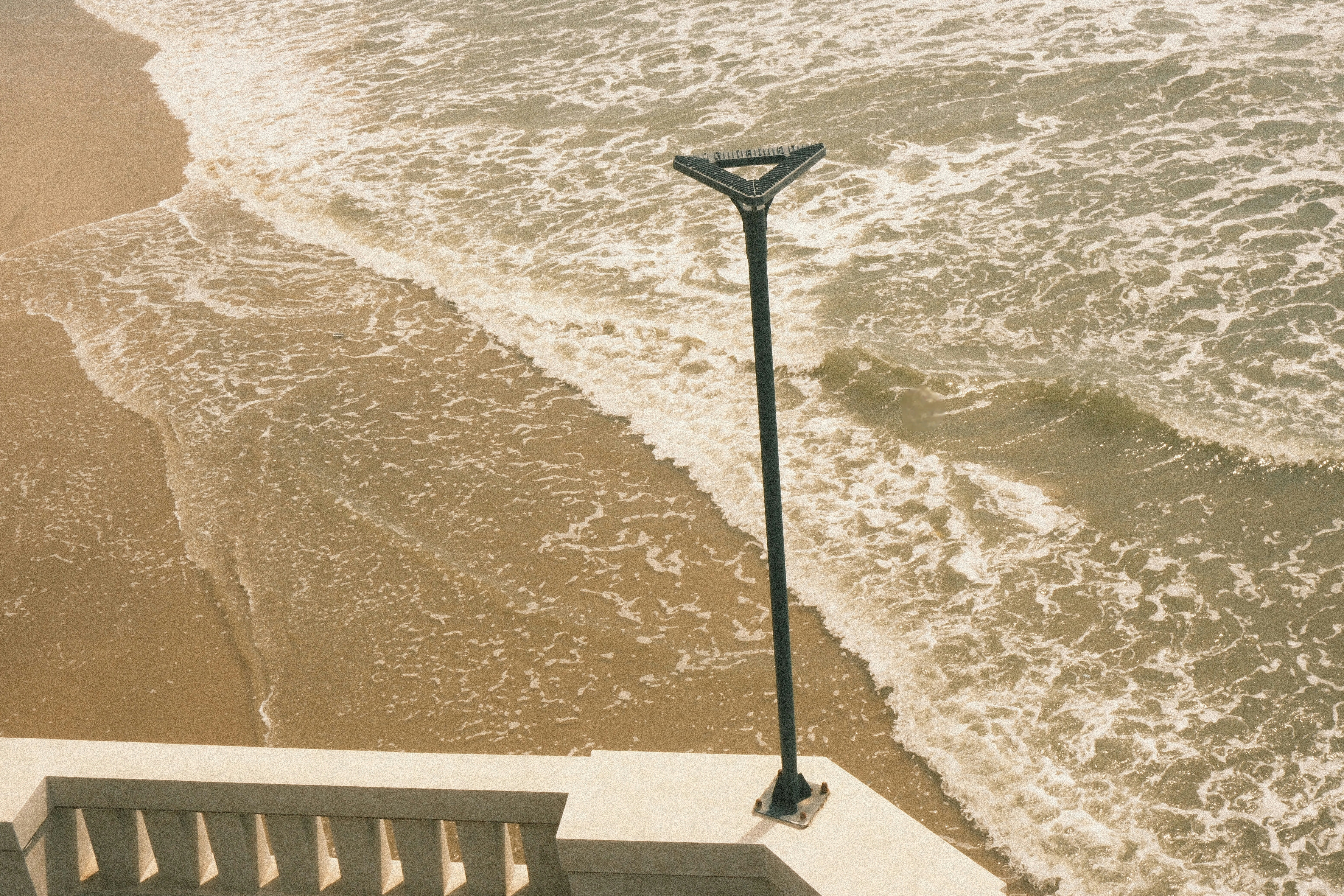 Dune-side Promenade: Aerial View of Wave-Patterned Shore from a Parapet