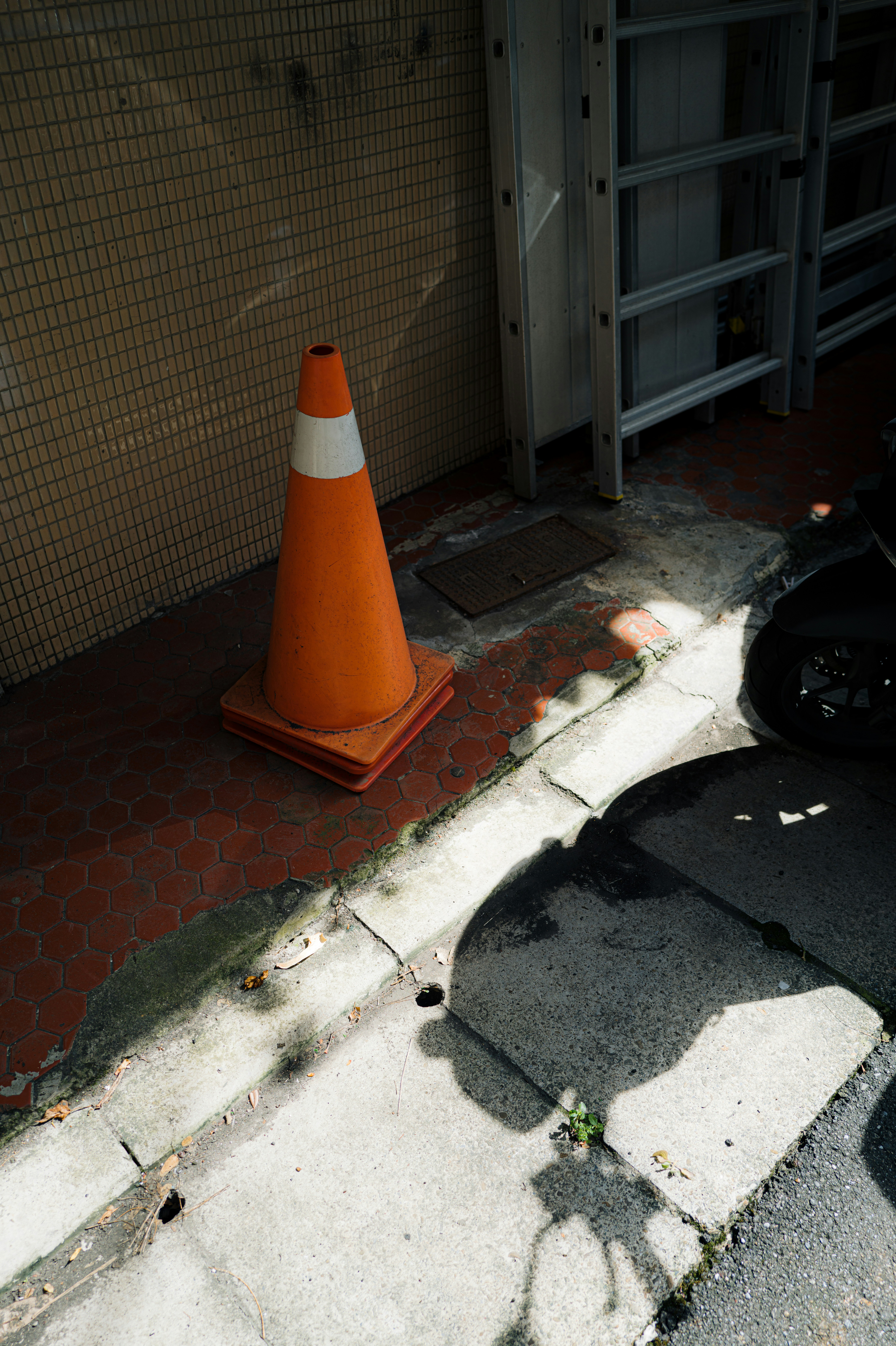 Orange Cone Anchor: Sunlit Sidewalk and Shadowed Street