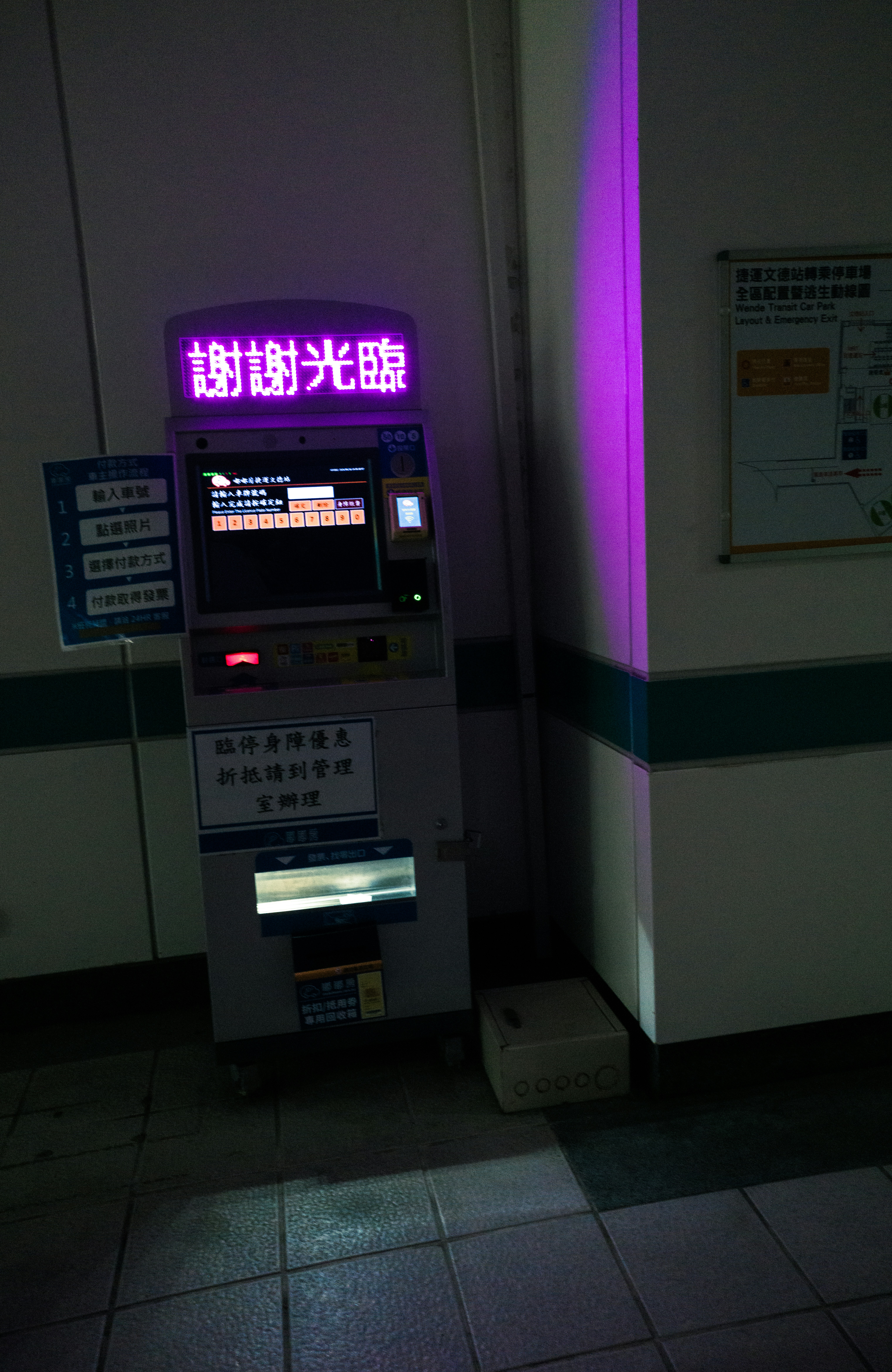 Neon-lit ticket kiosk in a dim station corridor