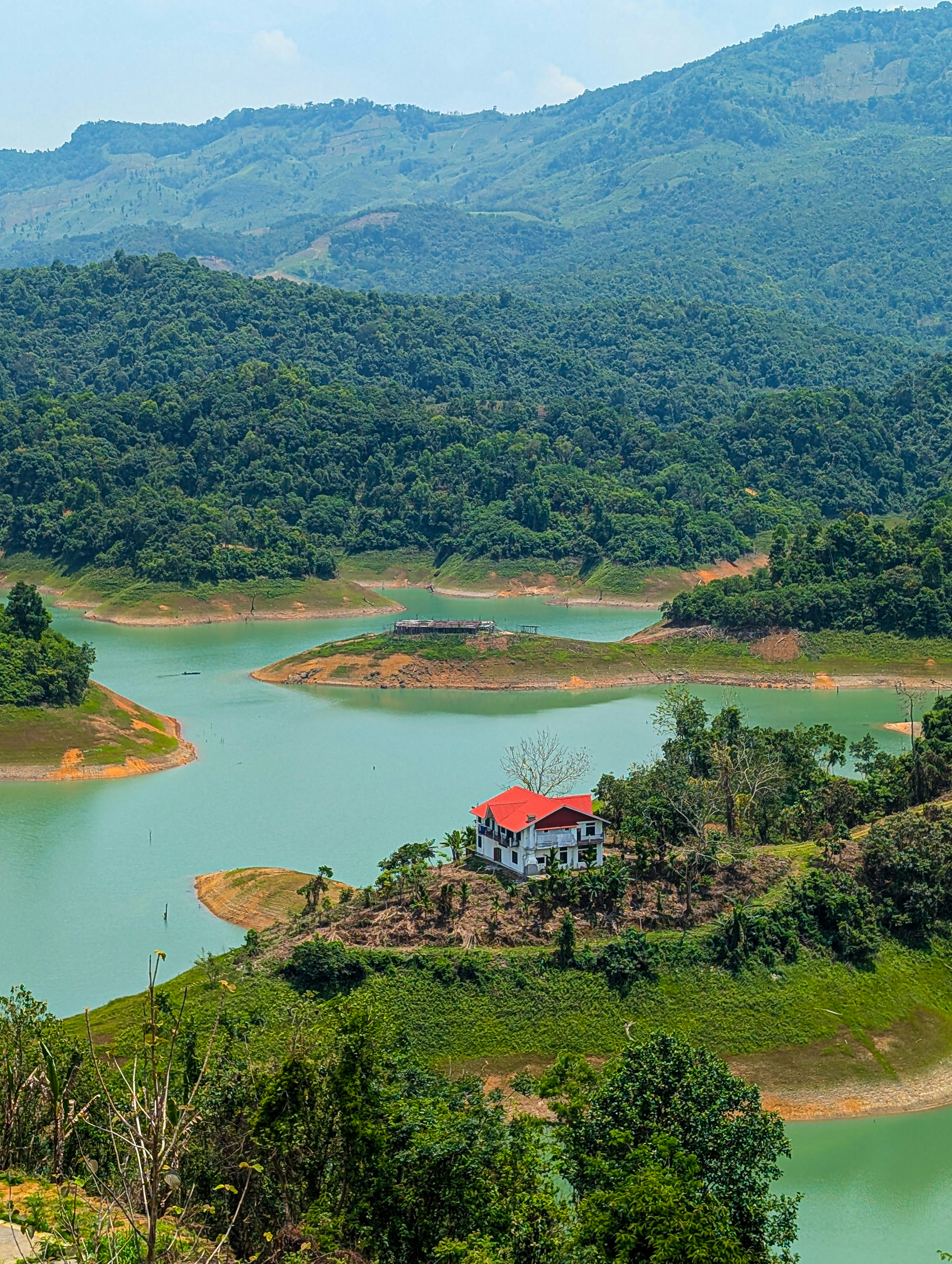 Red-roofed villa on a small peninsula amid turquoise reservoirs