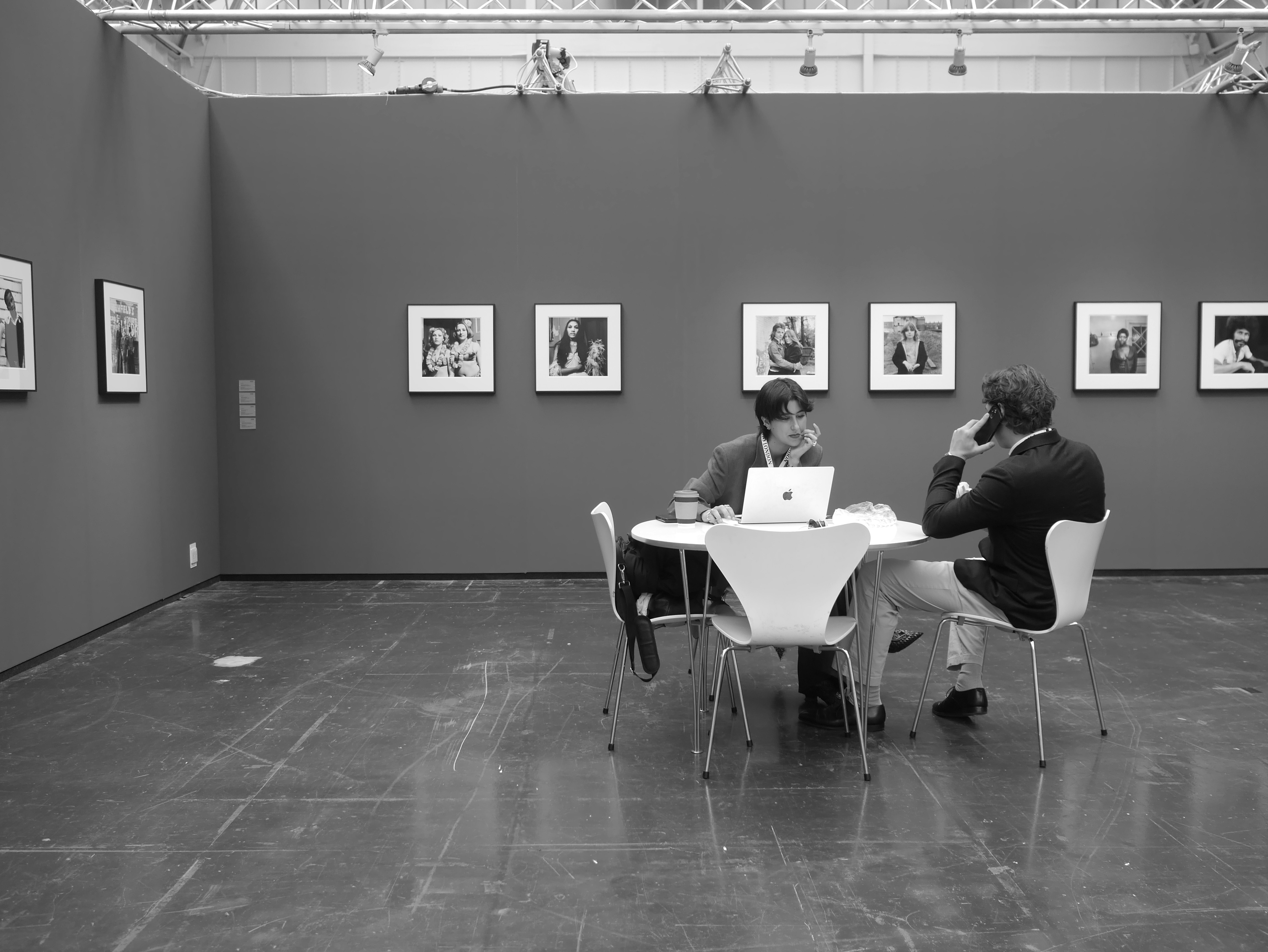 Two men talking at a table in an art gallery. photo – Free Laptop Image ...