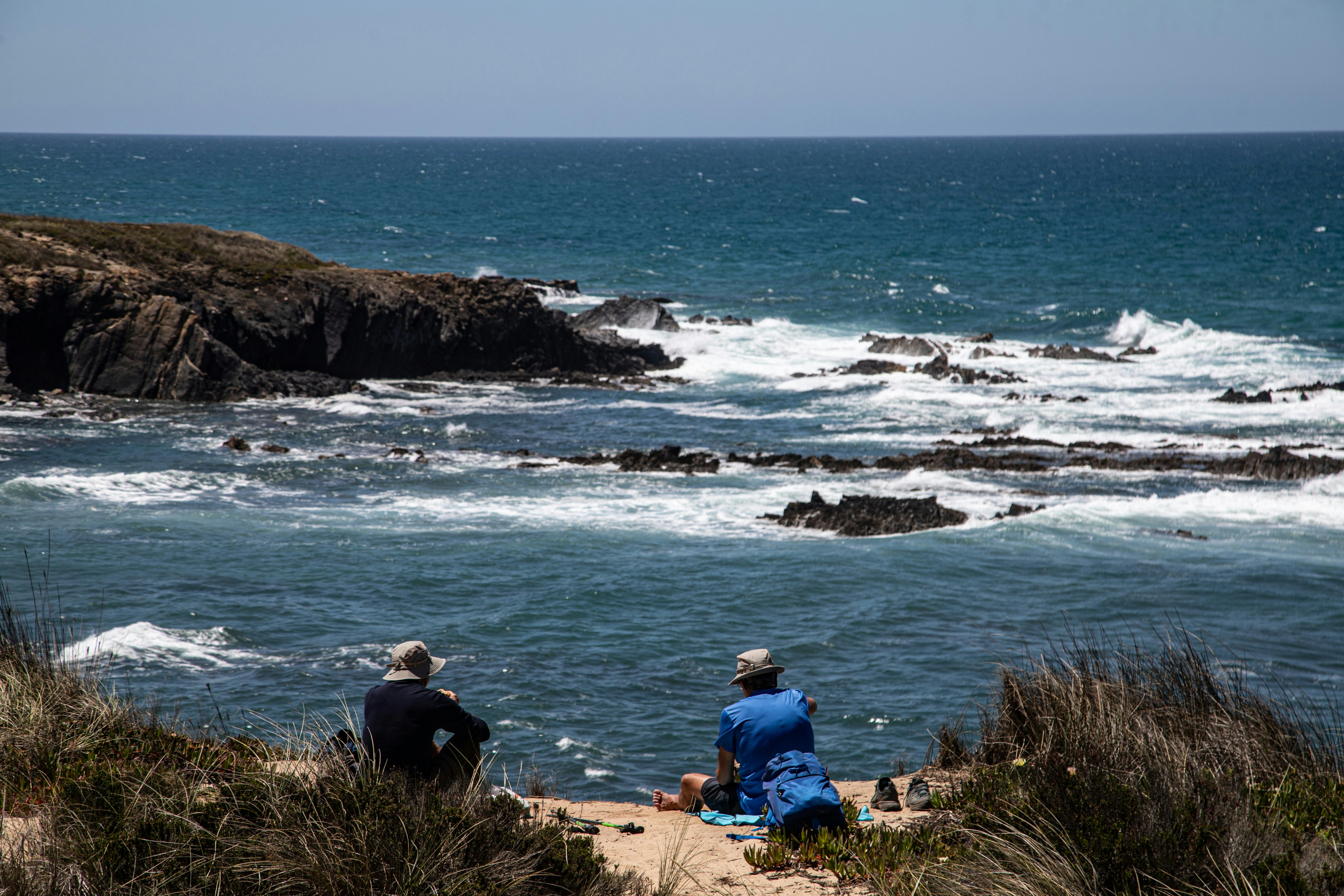 Coastal Conversation: Two Figures Quietly Observing a Distant Break