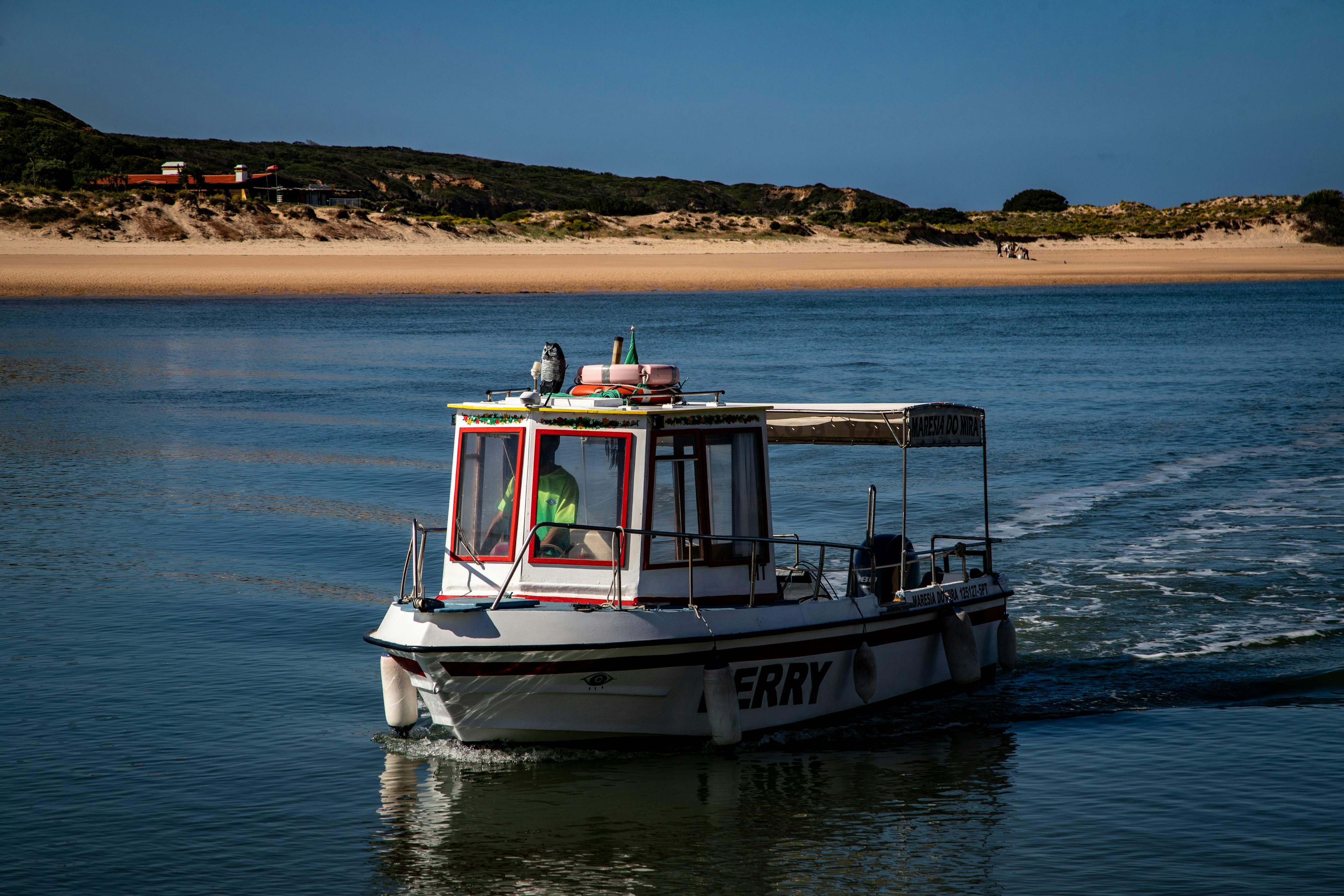 Red-and-White Fishing Boat carving a wake along a tranquil shoreline
