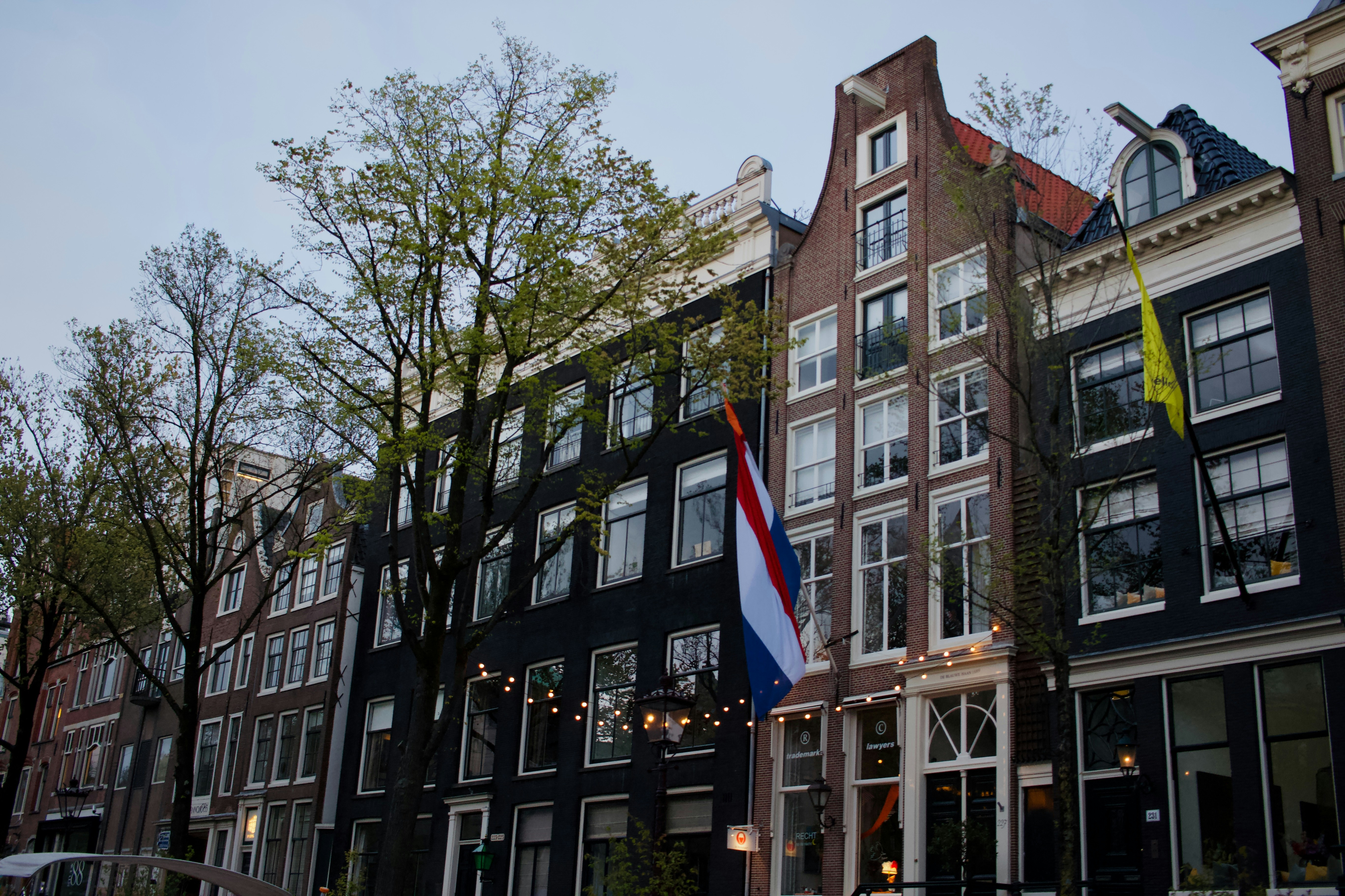 Row of Dutch townhouses under string lights and a fluttering flag