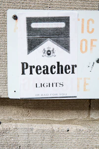 Preacher Lights: A Weathered Sign Adrift on Concrete