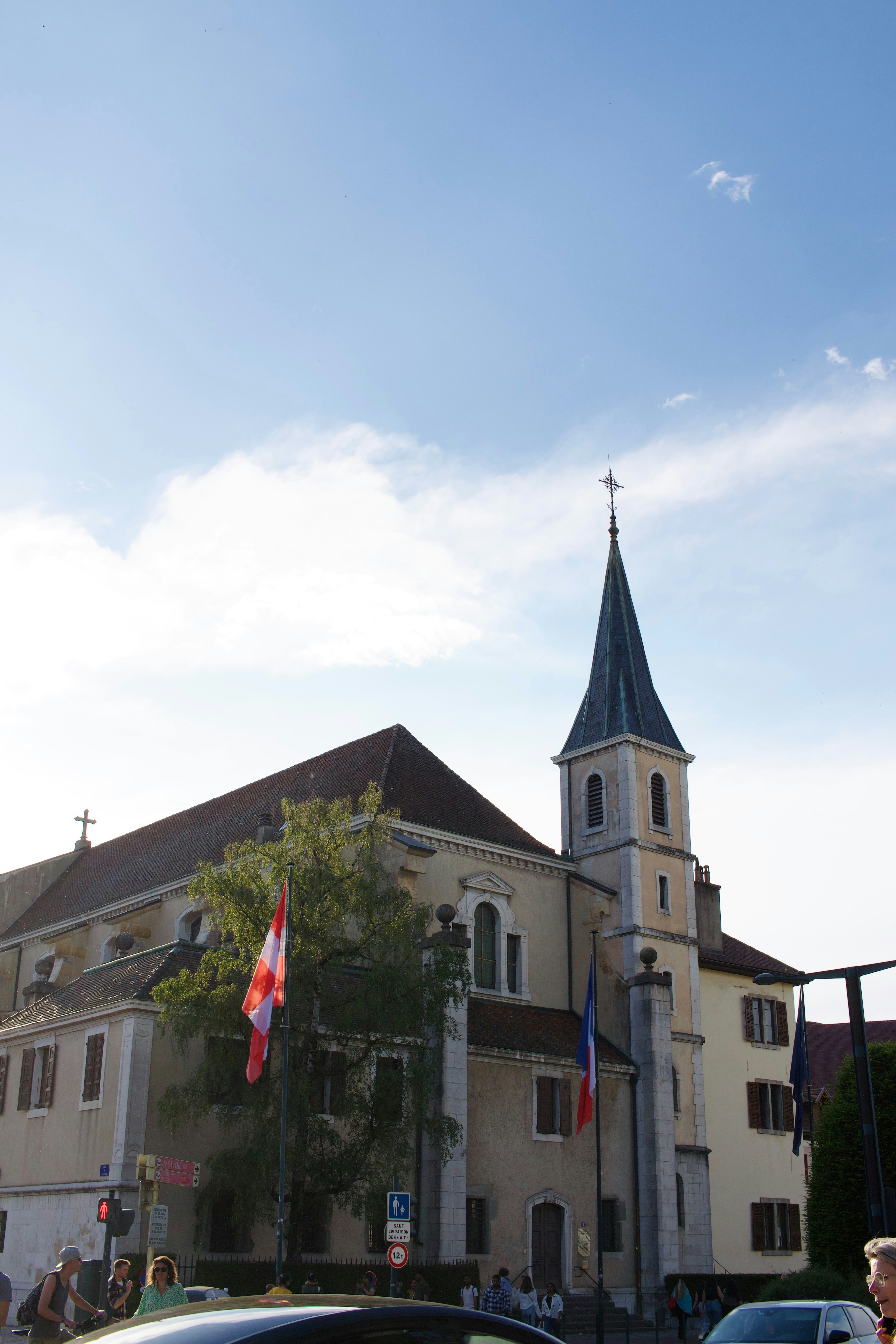 Stone Church at Dusk: Flags, Clock Tower, and Town Square