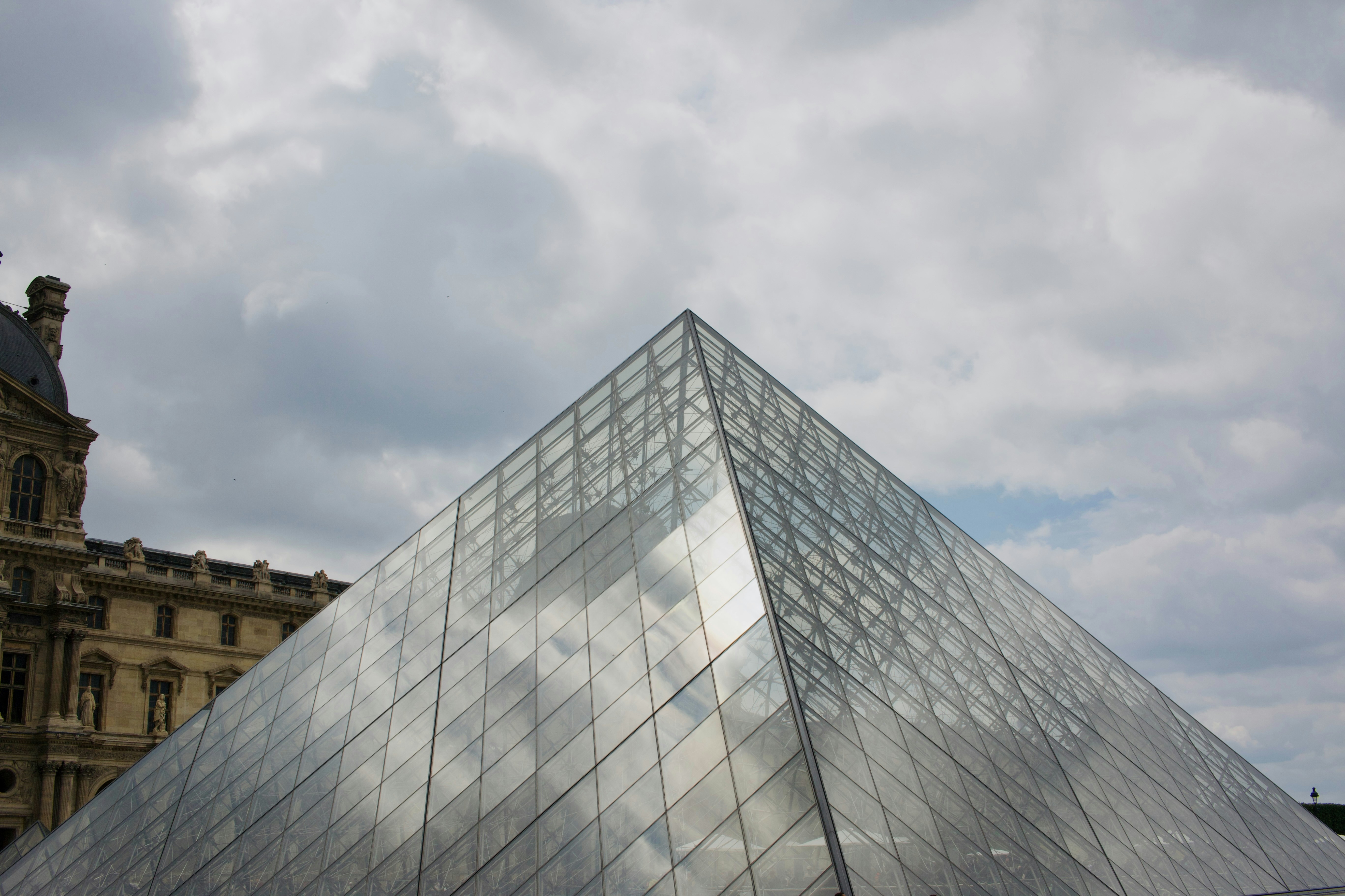 Geometric Glass Diamond: The Louvre Pyramid Against a Cloudy Sky