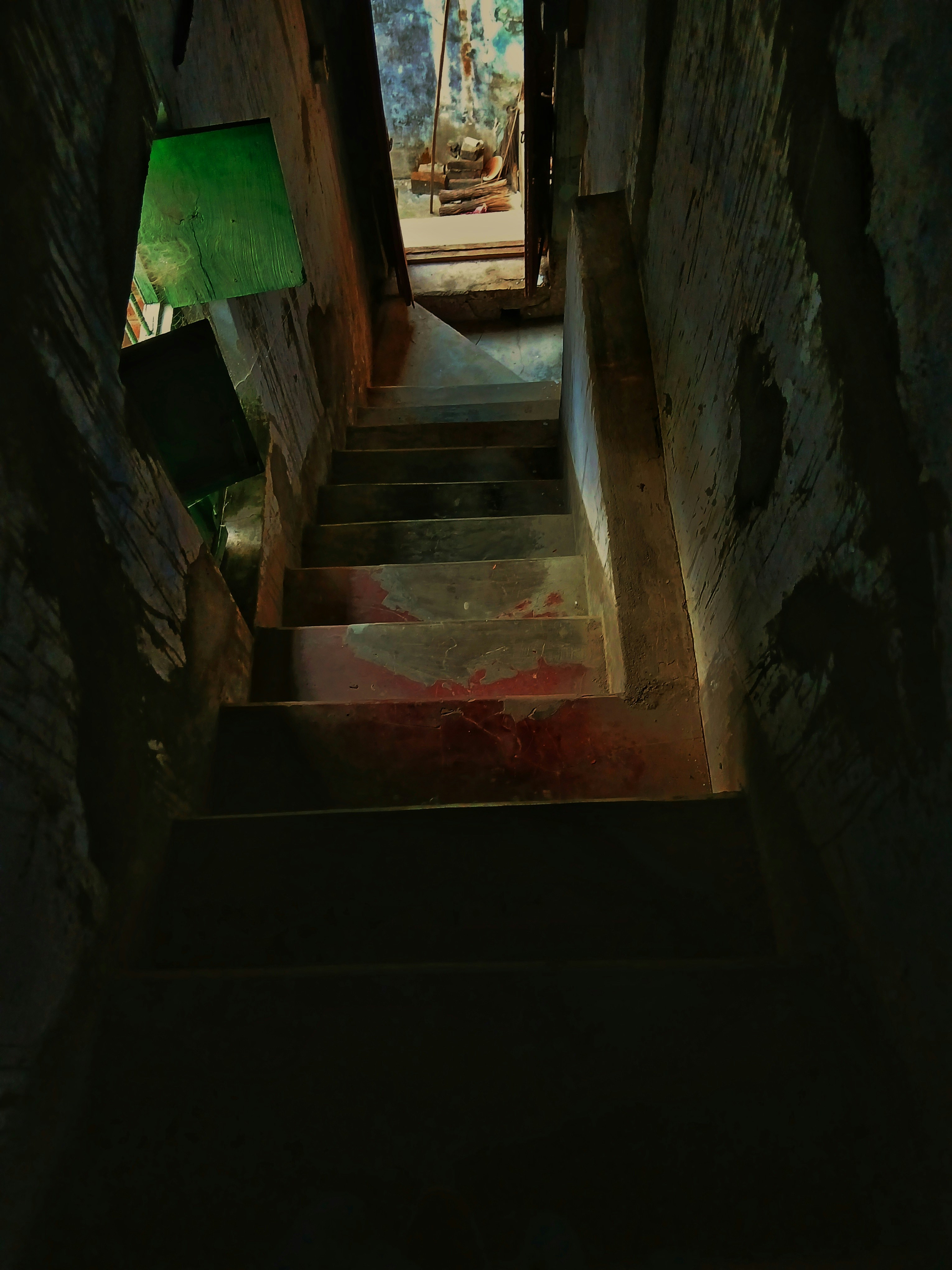 Descent into Dim Light: Weathered Stairwell to a Glimpse of Outside