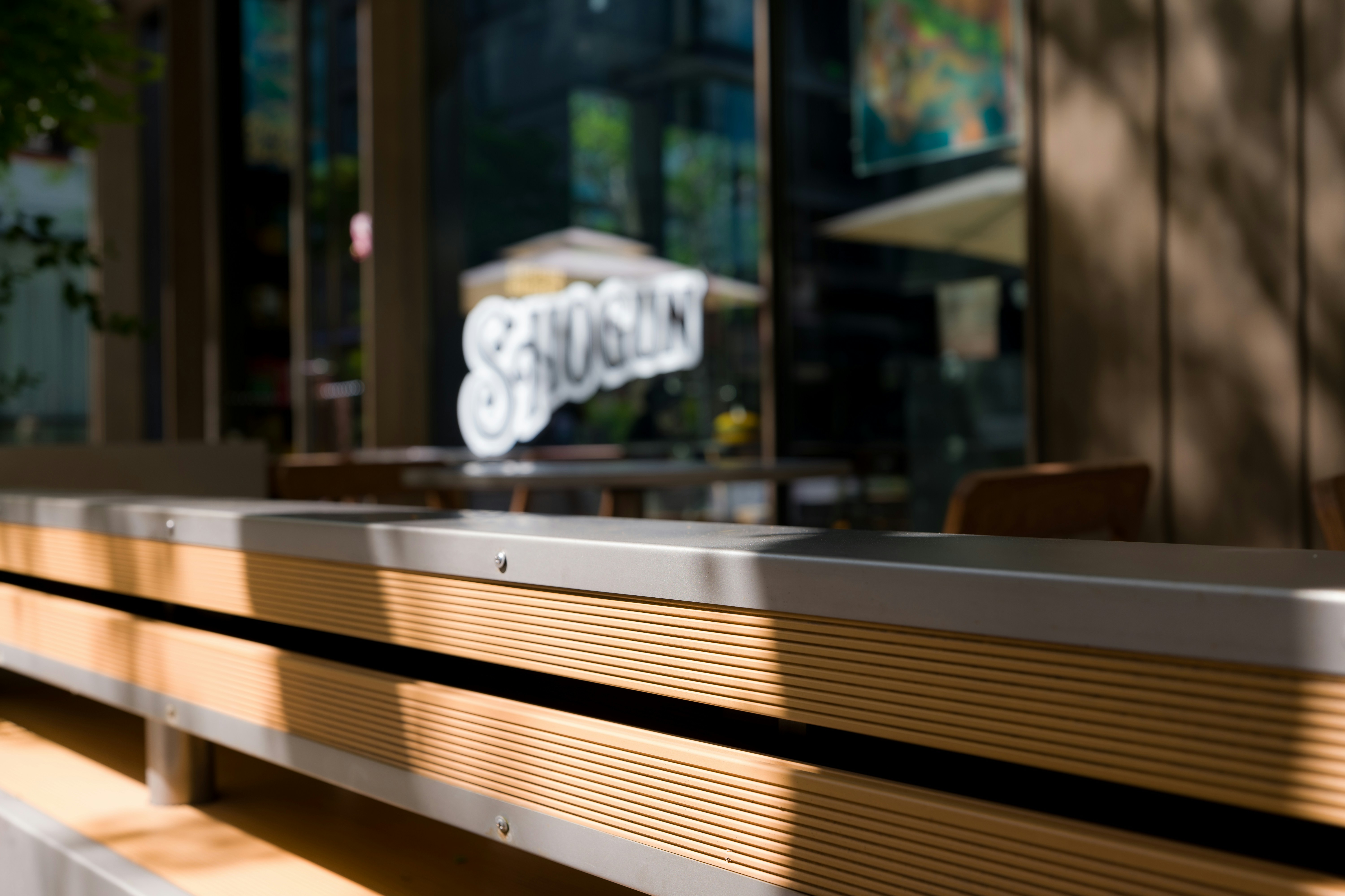 Sunlit Bench Lines Meet a Quiet Café Window