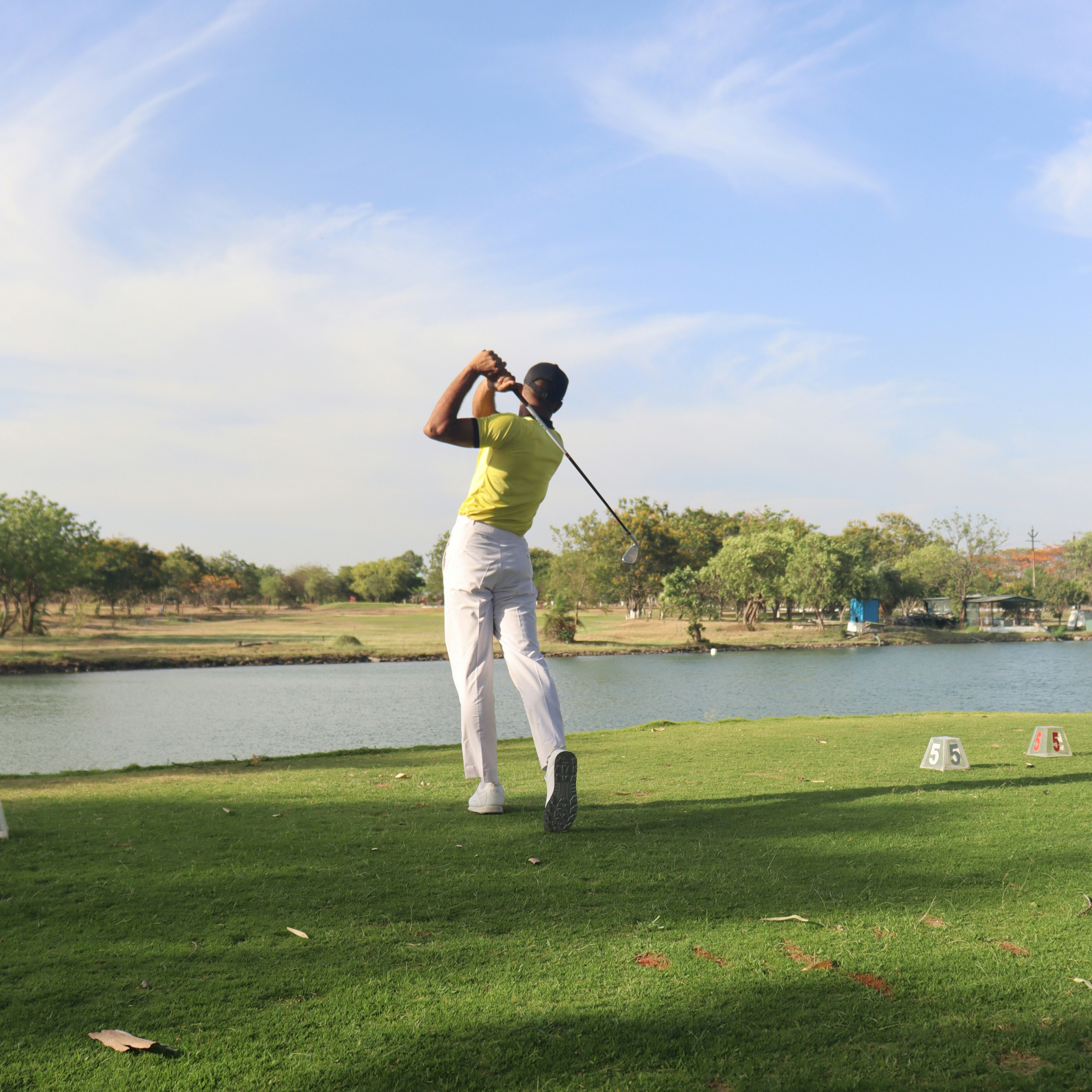 Swinging for Distance: A golfer mid-swing against a peaceful lakeside backdrop