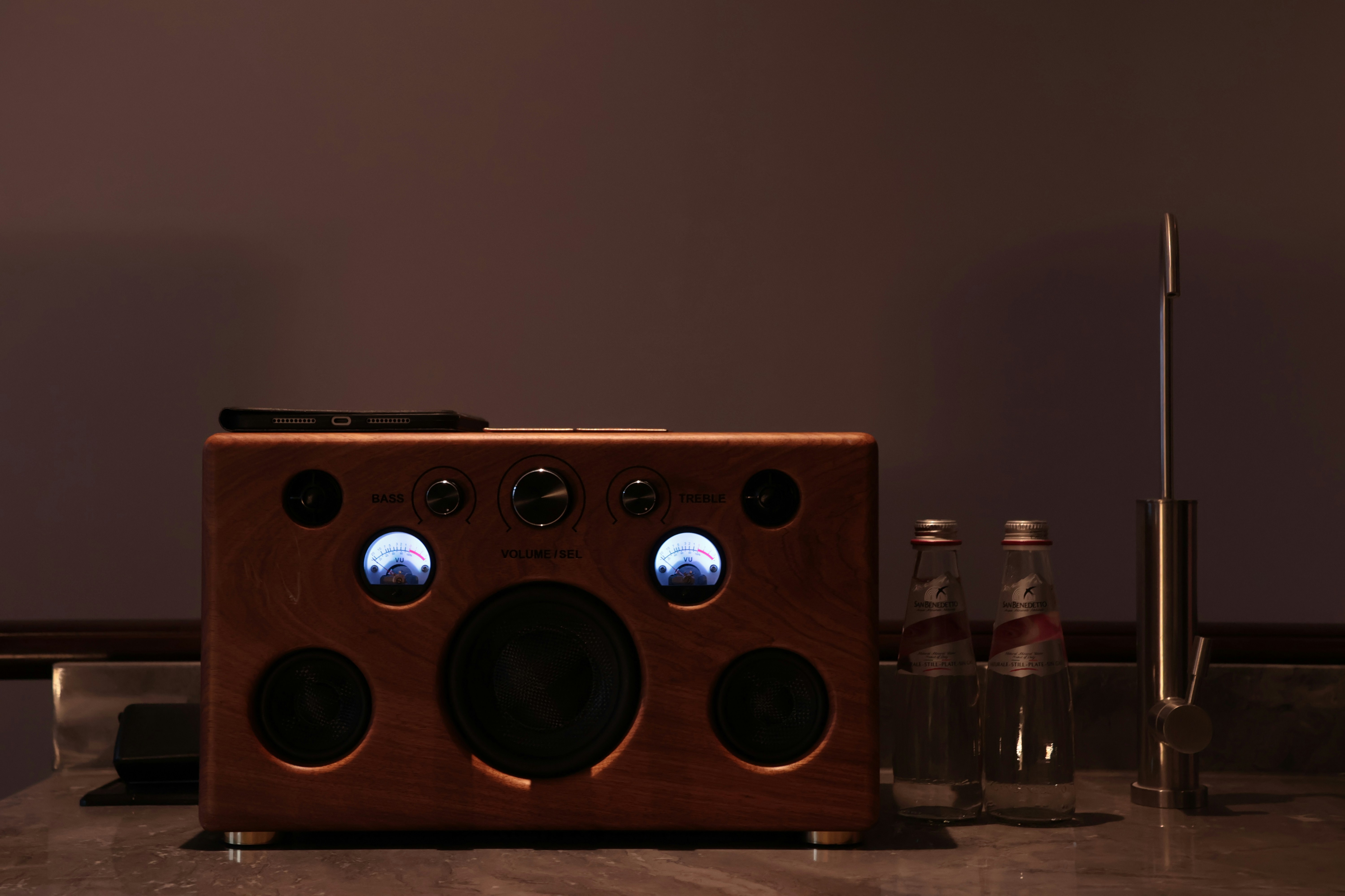 Warm-lit Wood Speaker with Soda Bottles and Metallic Stand