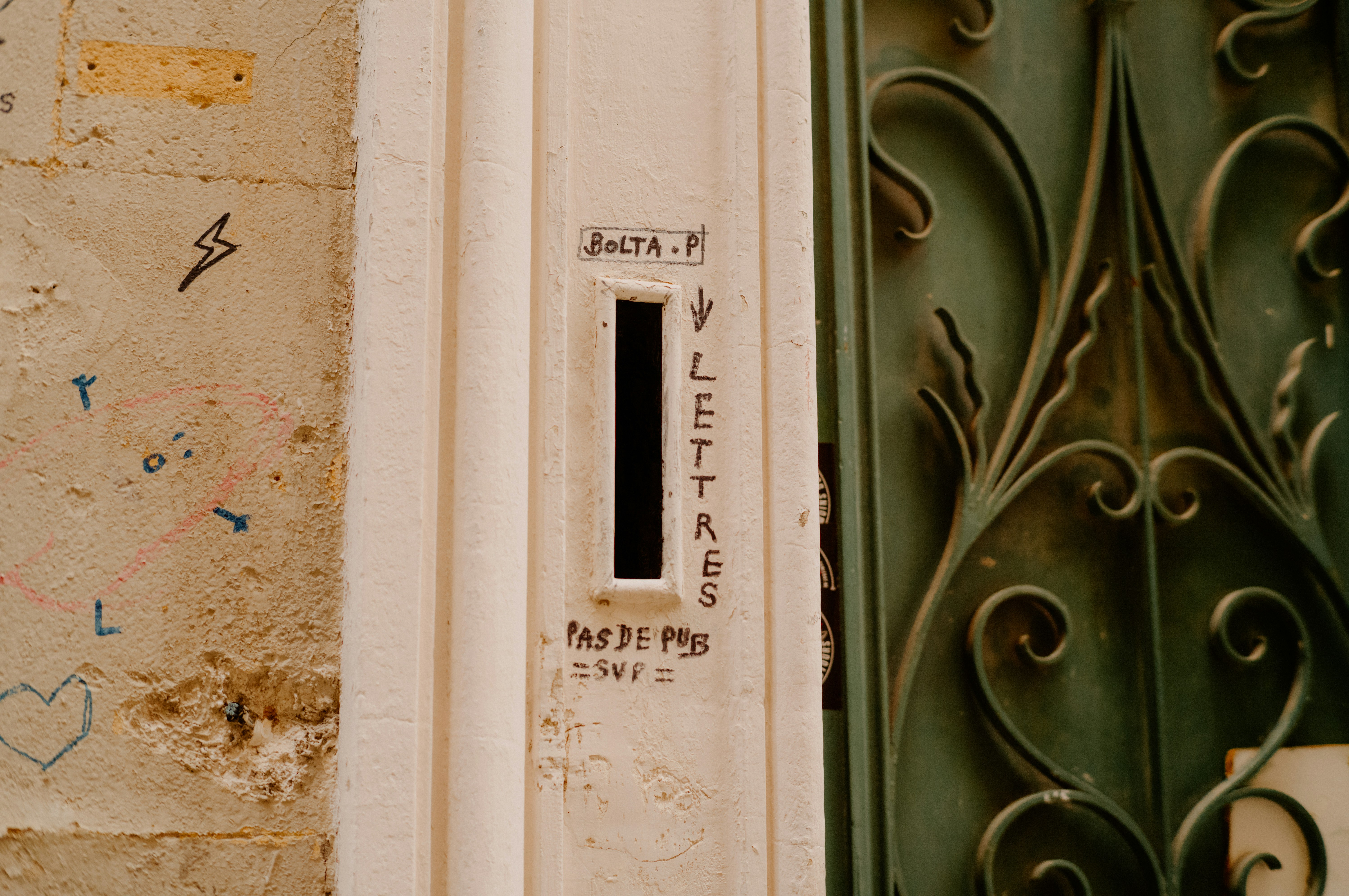 A Weathered Doorway: Graffiti, Metalwork, and a Narrow Slot