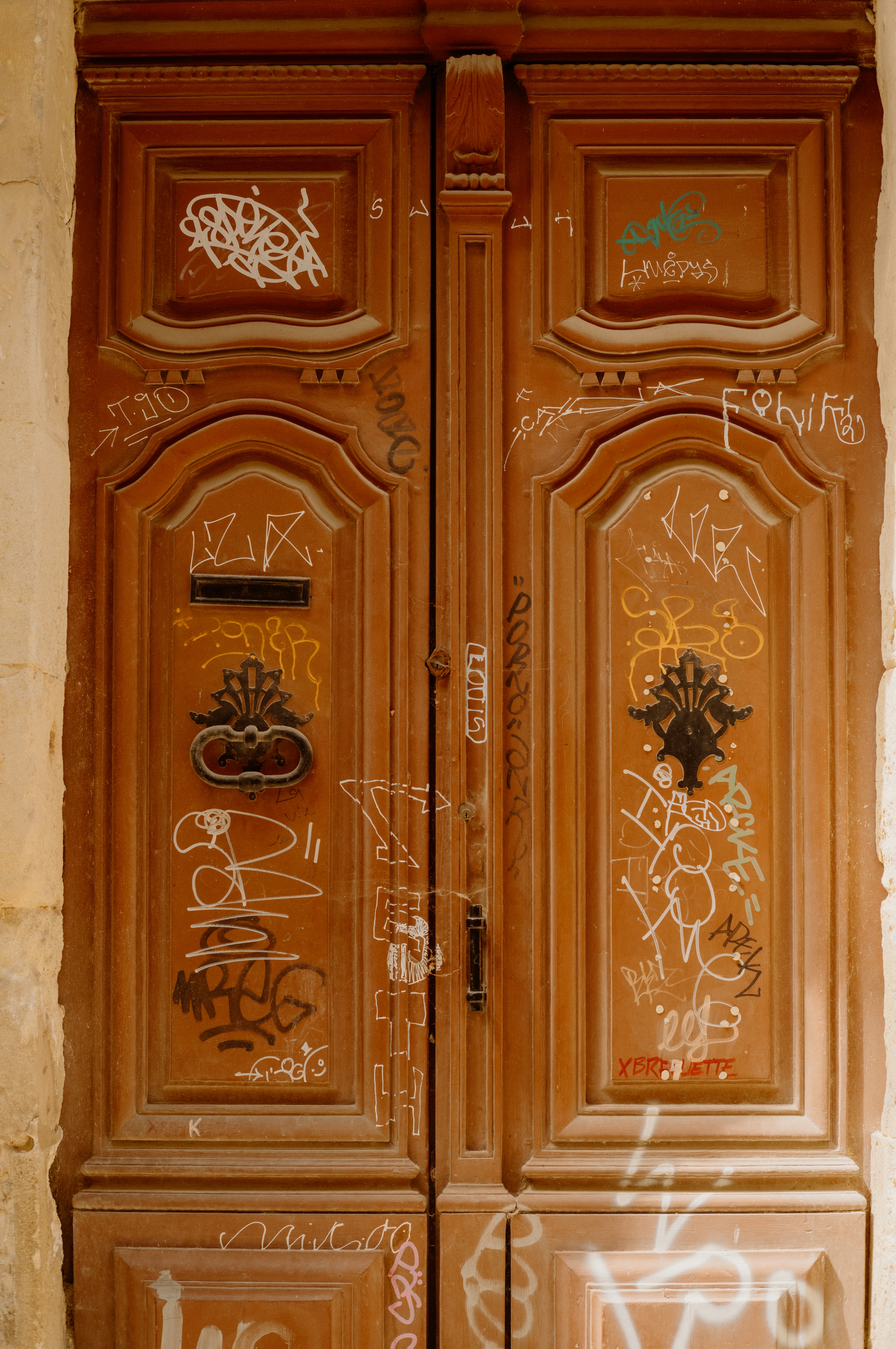 Grafitti-Dusted Doorway: A Weathered Portal of Color and Carvings