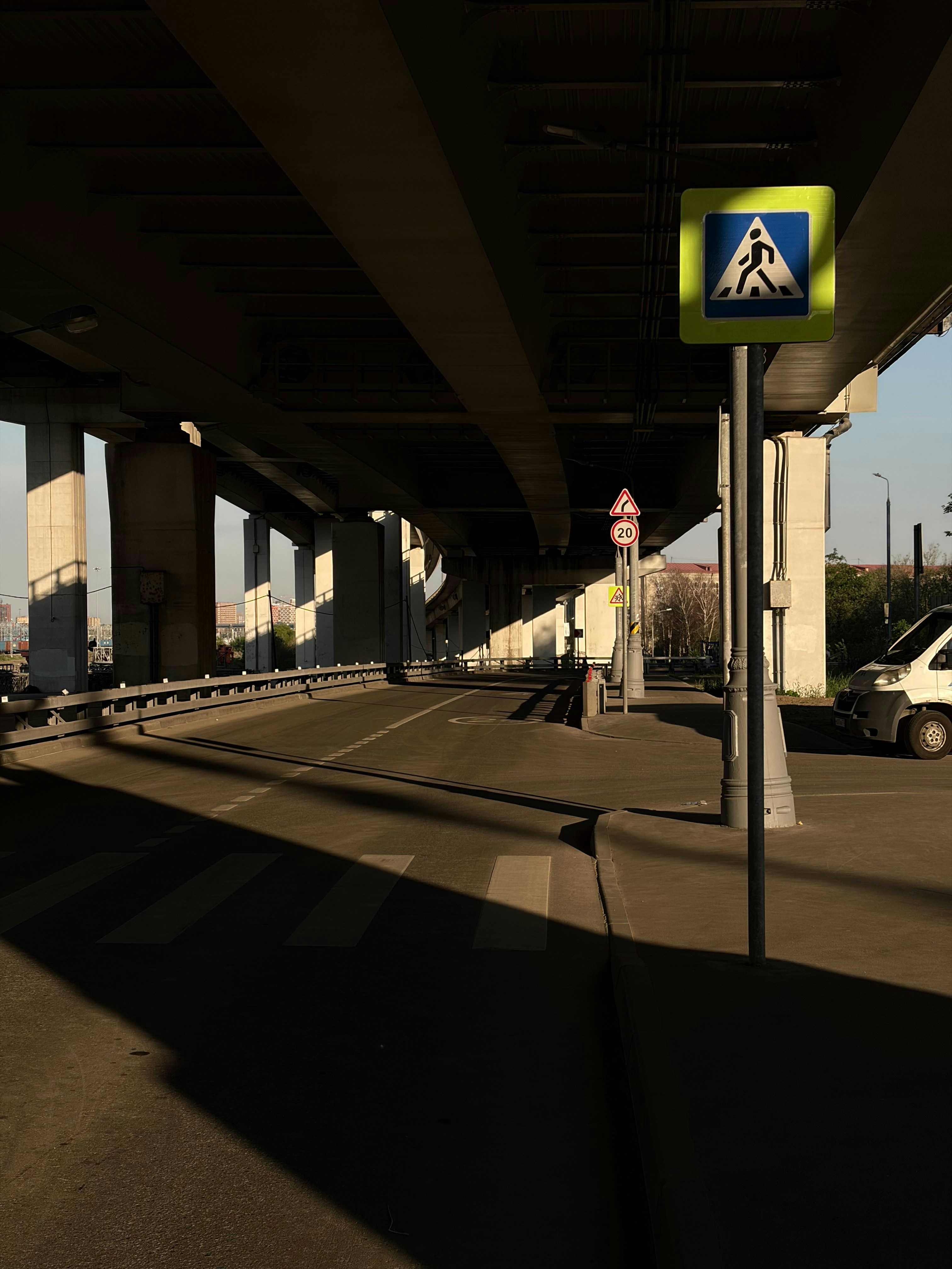 Under the Overpass: Sunlit Street Corridor with Pedestrian Crossing Sign