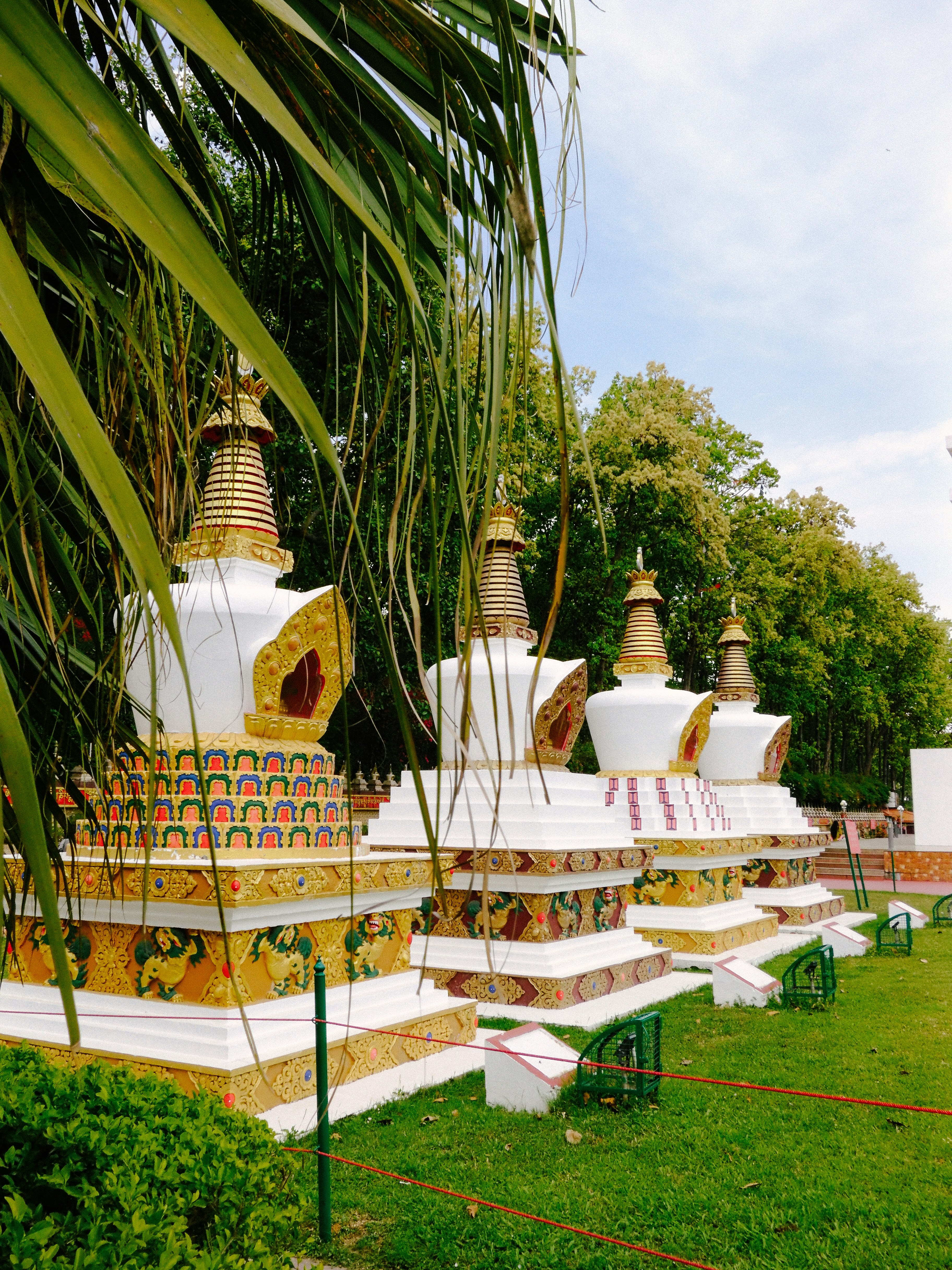 Row of gilded stupa silhouettes beneath tropical leaves