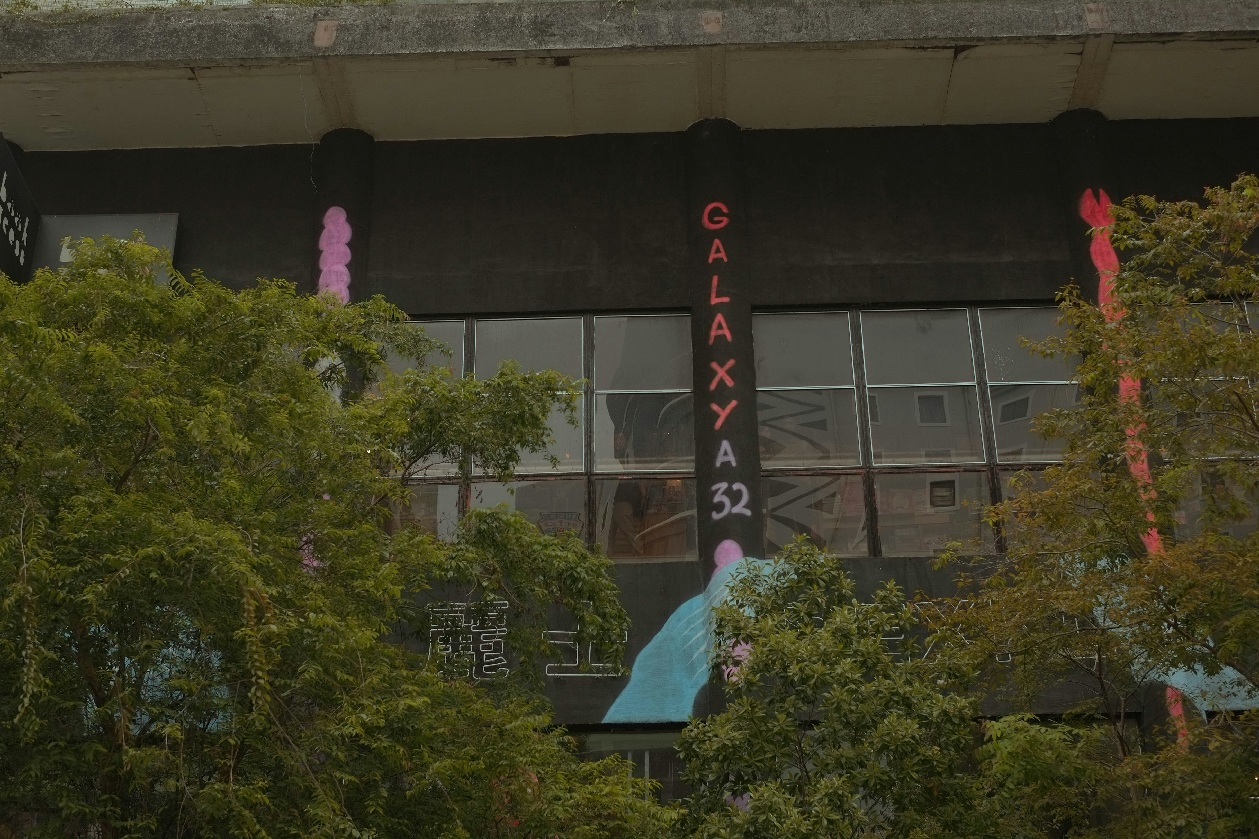 Galaxy Signage Emerging from a Forested City Facade