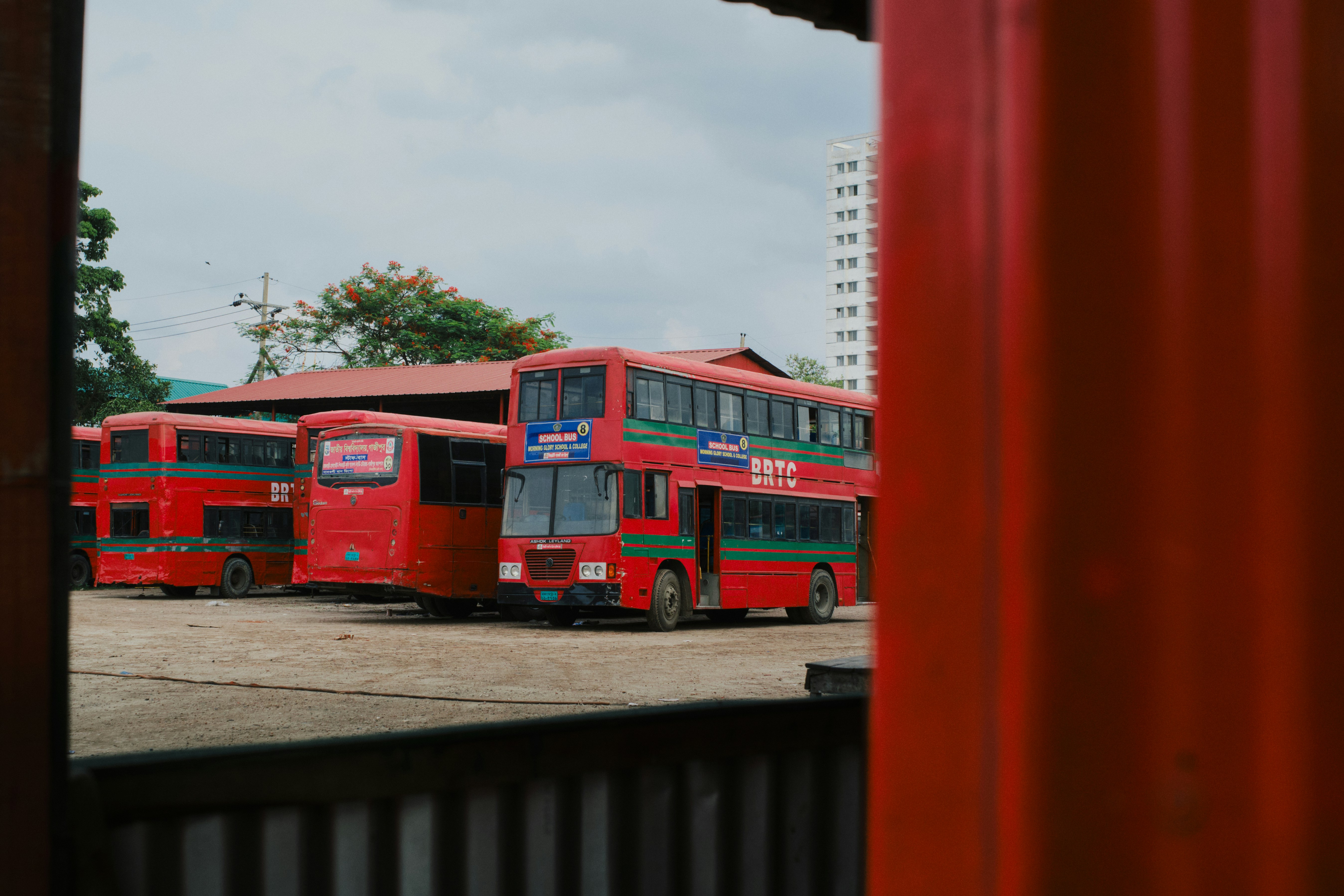 Red Fleet Rest: Buses Parked in a Yard Framed by a Crimson Structure