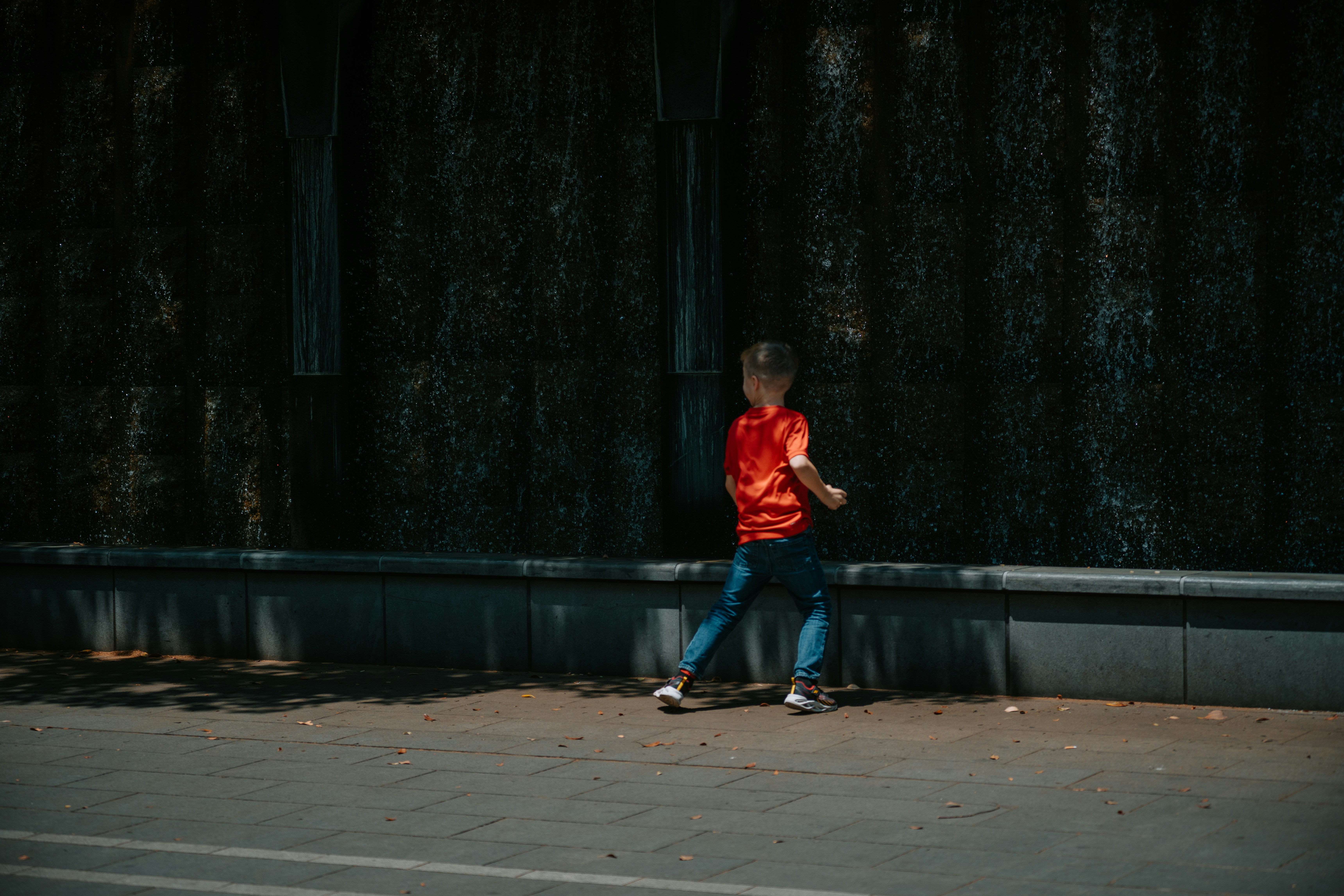 Red Shirt, Dark Wall, Moving Shadow: A Street Moment
