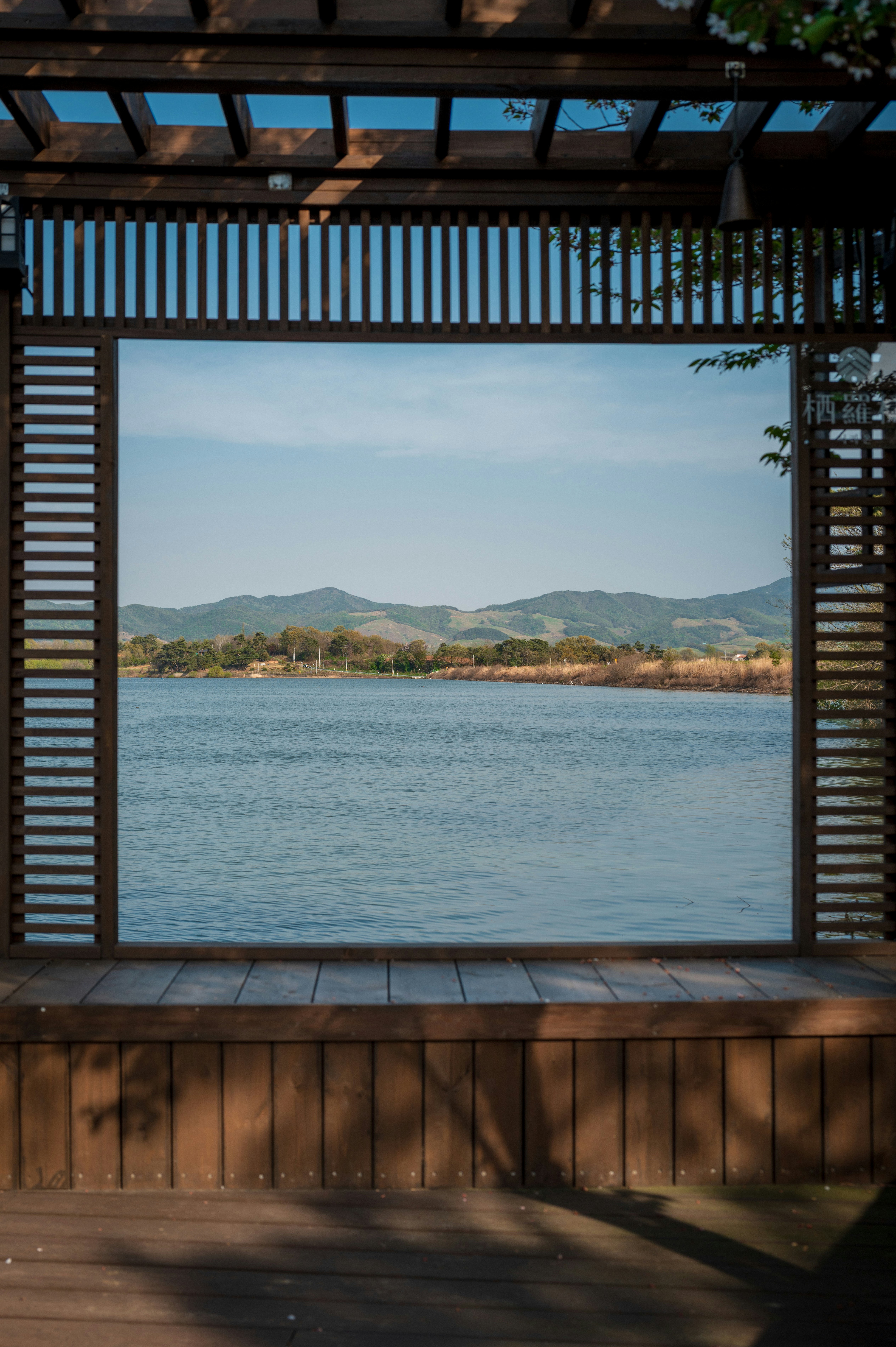 Framed by Timber Lattice: A Tranquil Lake View through a Sunlit Pergola