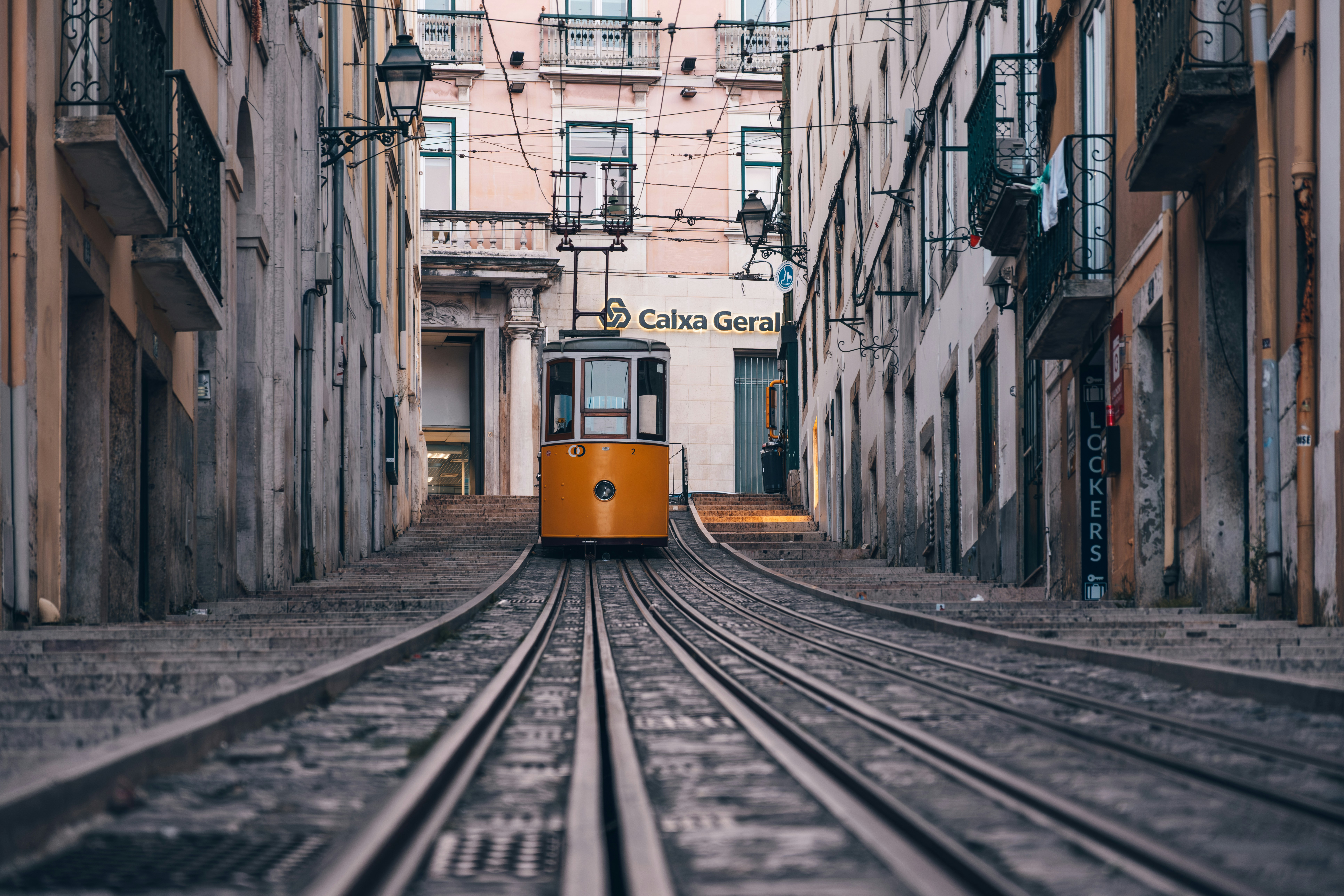 Orange tram in a narrow Lisbon-like street lined with old buildings