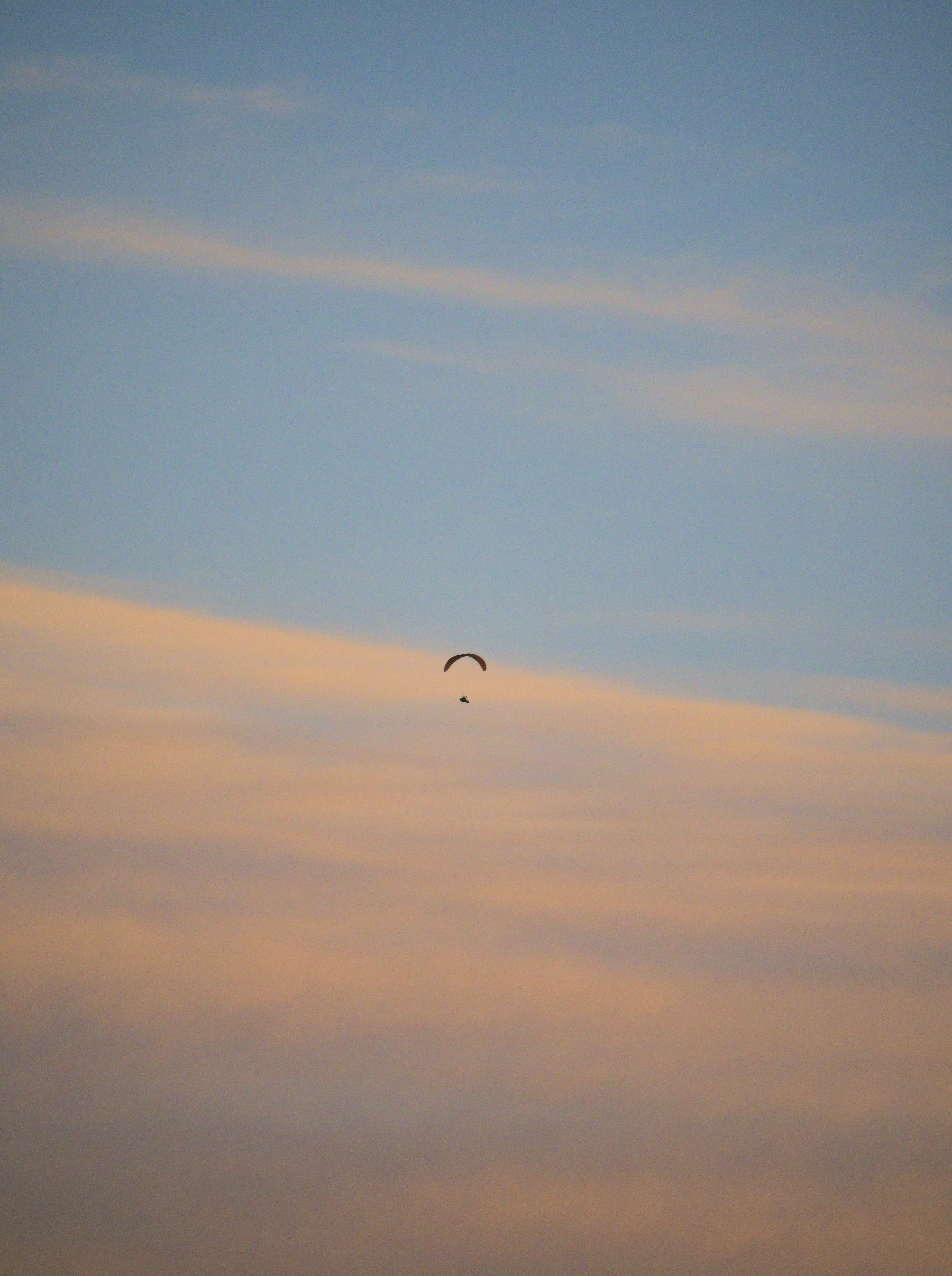 Midair Moment: A Tiny Silhouette Against Sunset Clouds