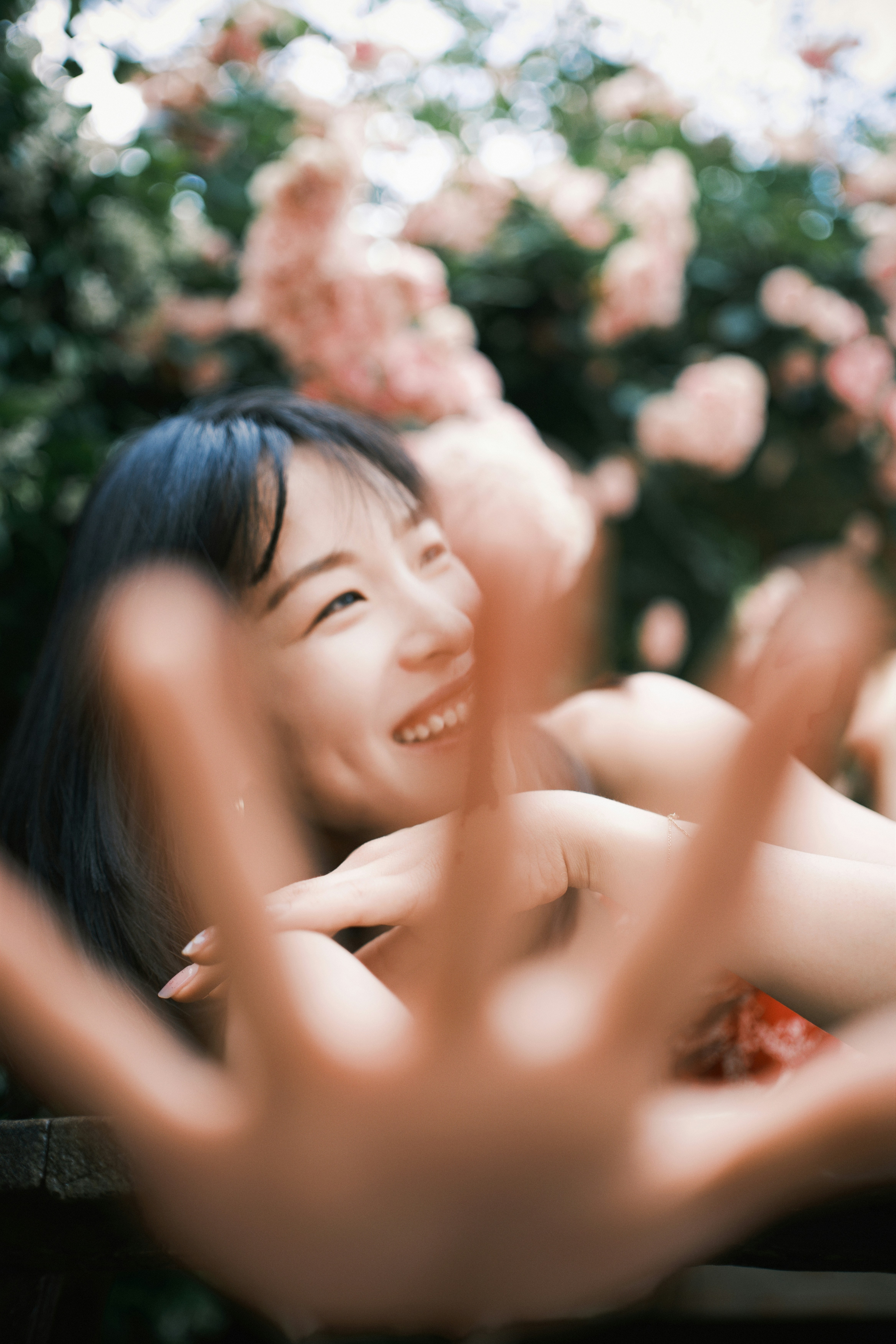 Young woman smiling amidst blooming pink roses