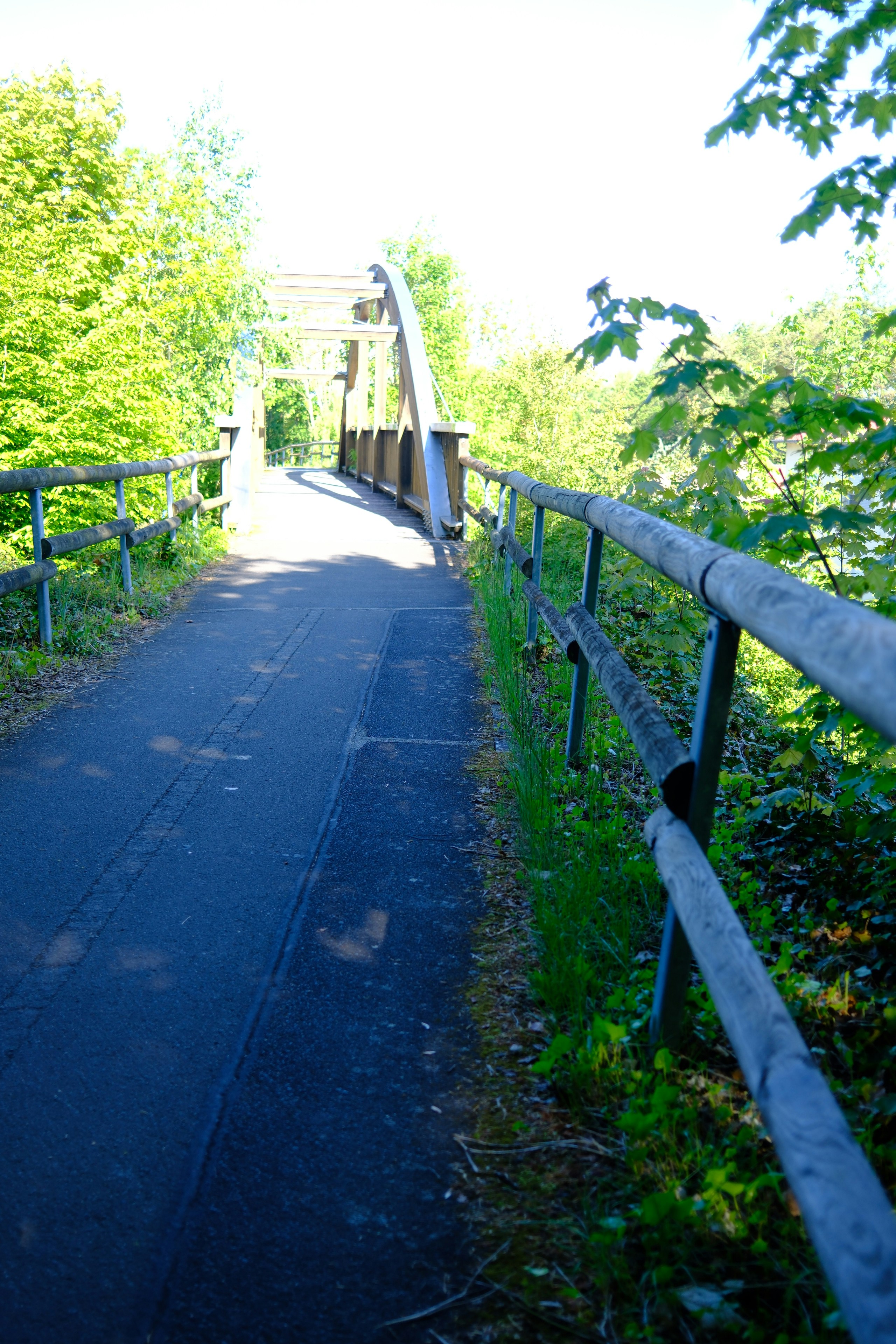 Pathway to the Bridge: A Sunlit Ascent Over Green Railings