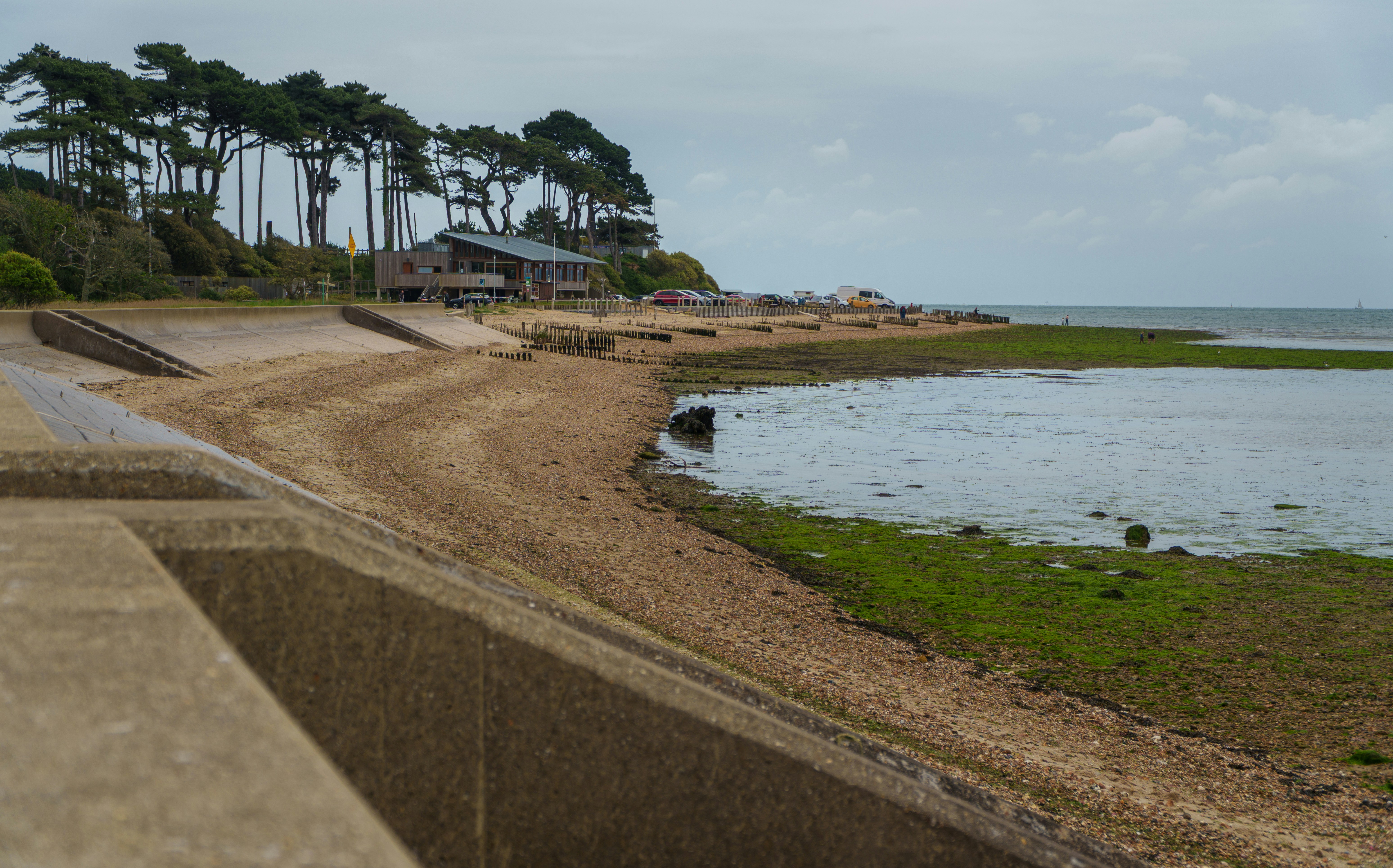Coastal Promenade: Tide, Concrete Barriers, and Distant Dunes