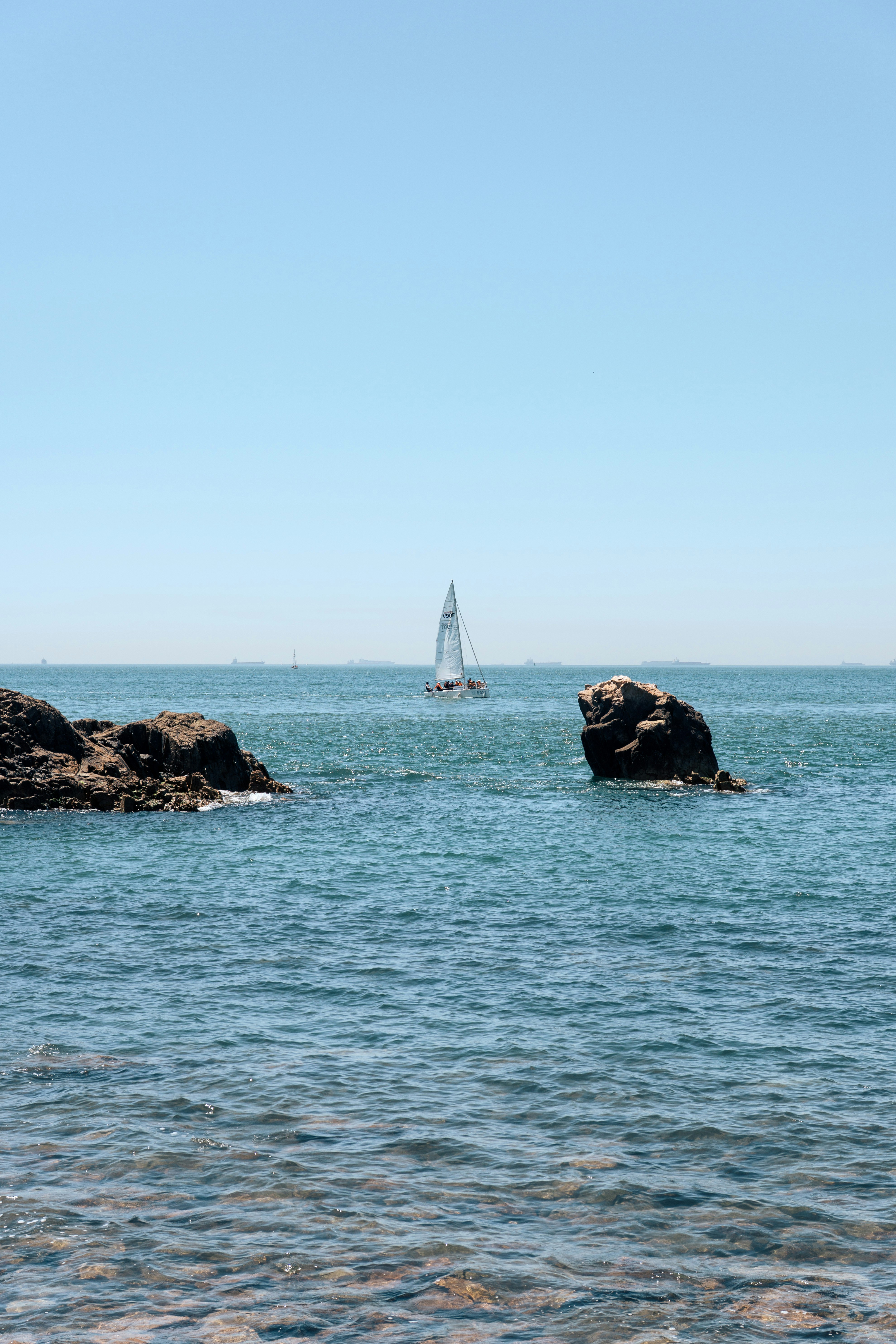 Sailboat on a Quiet Sea Between Two Rock Sentinels