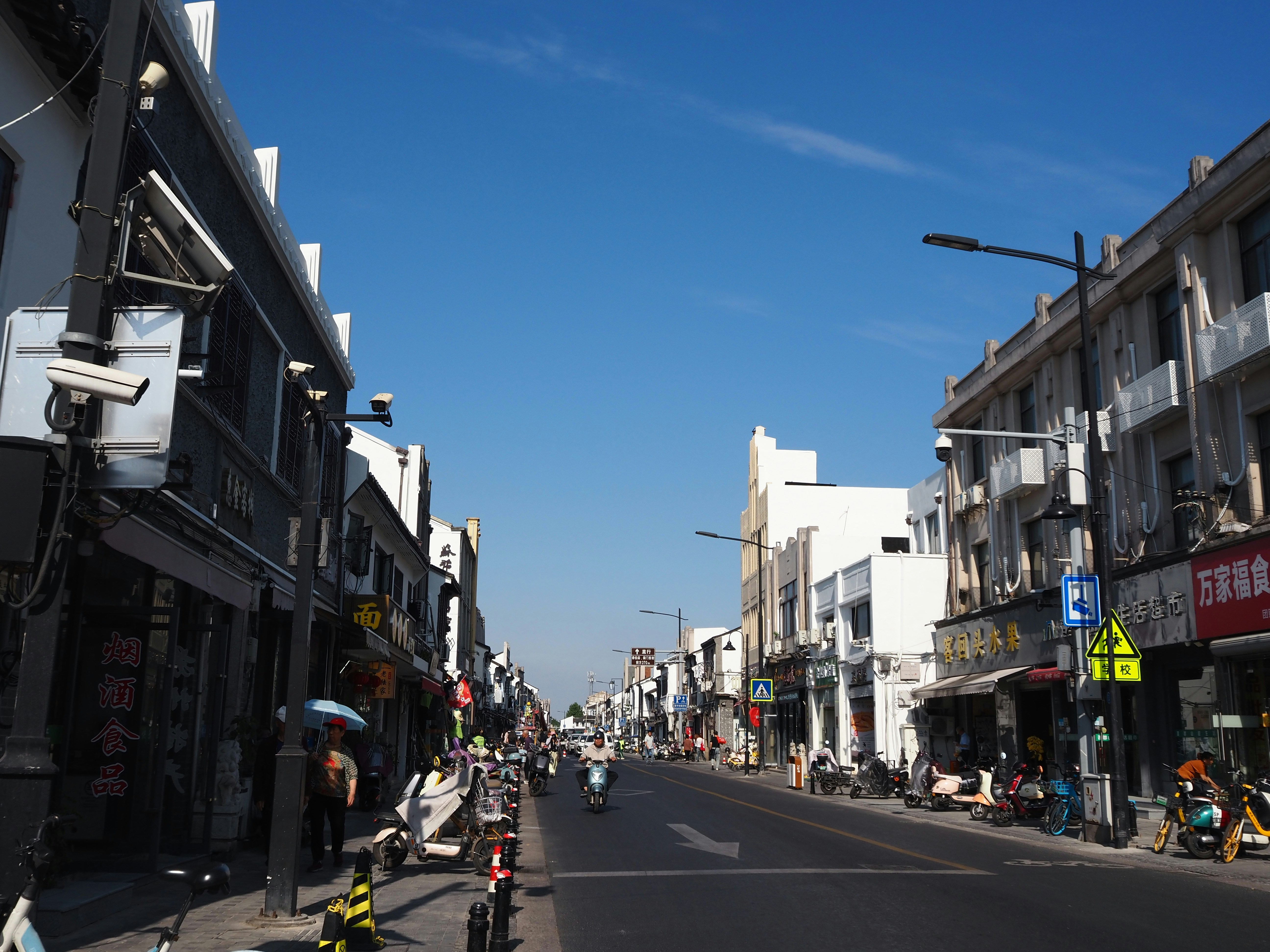 Street Corridor: A Sunlit Avenue of Shops and scooters
