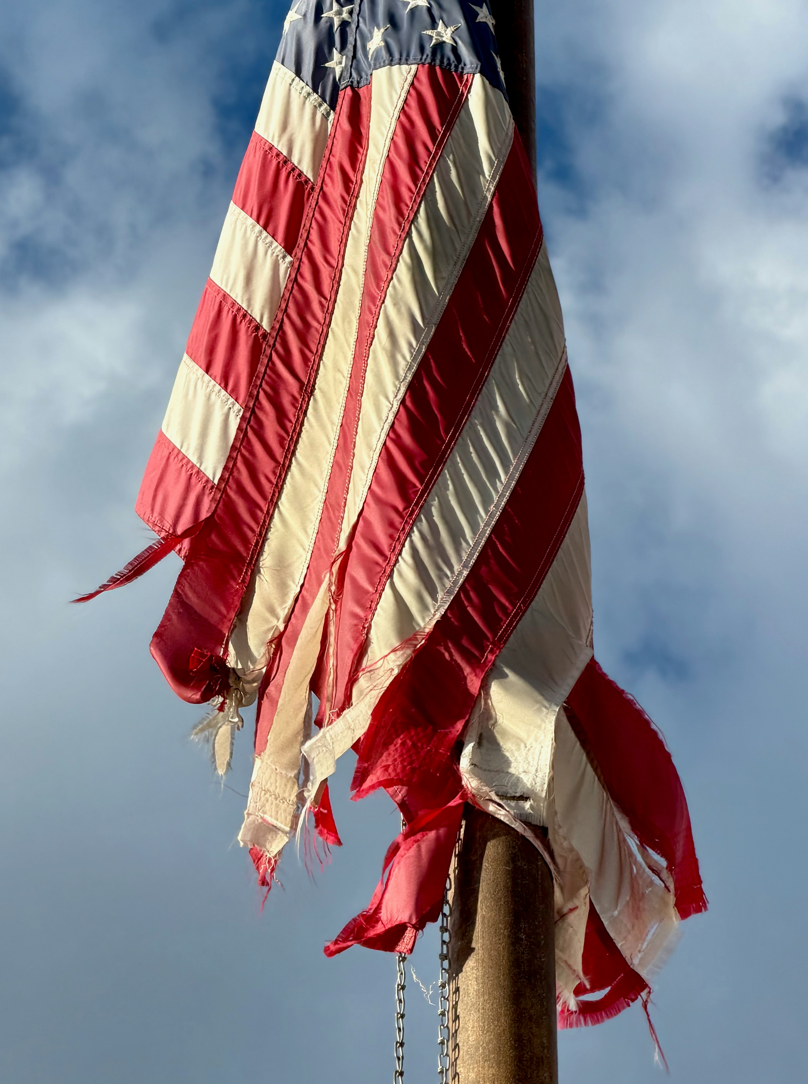 Tattered Flag on a Weathered Pole Reaching Toward a Brisk Sky