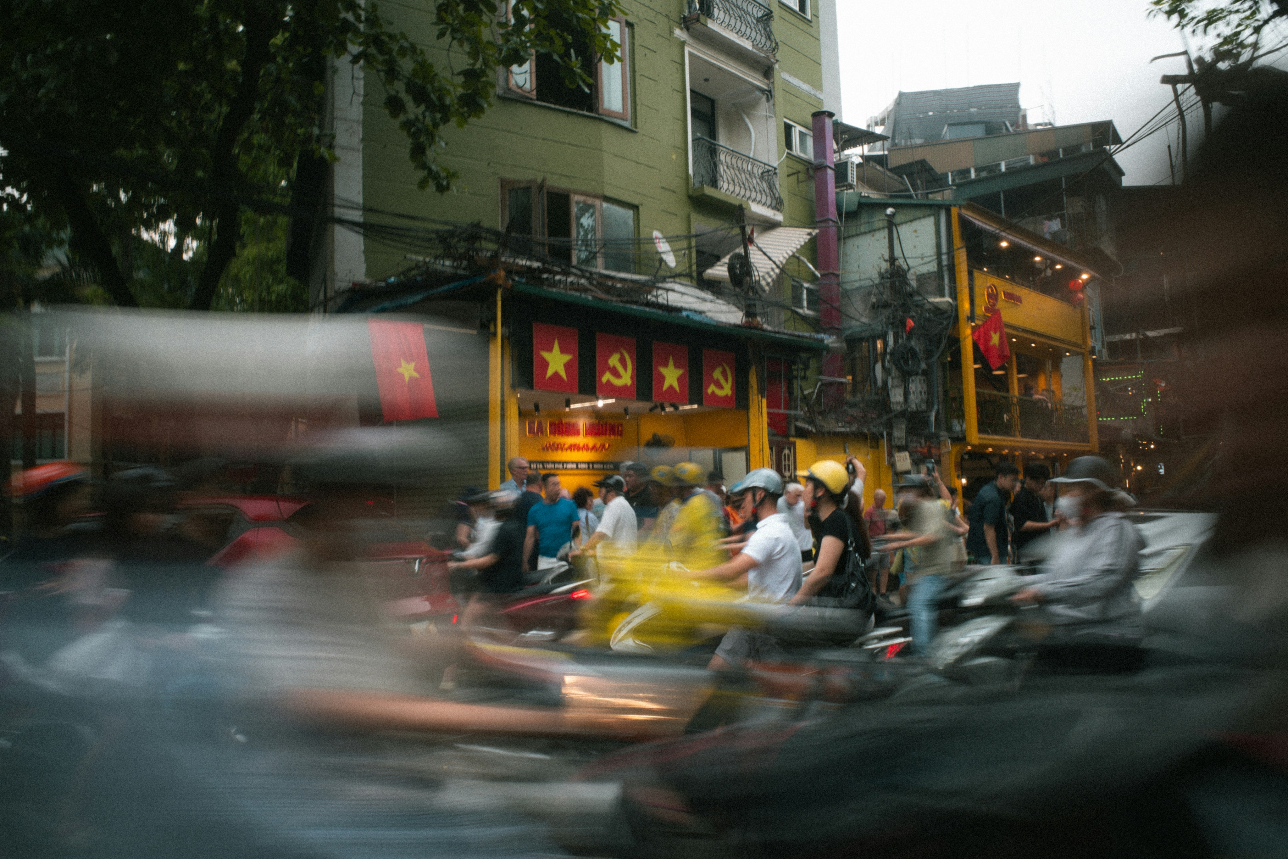 Motion Gate: Scooters and Starlit Flags Blur Through a Street Market