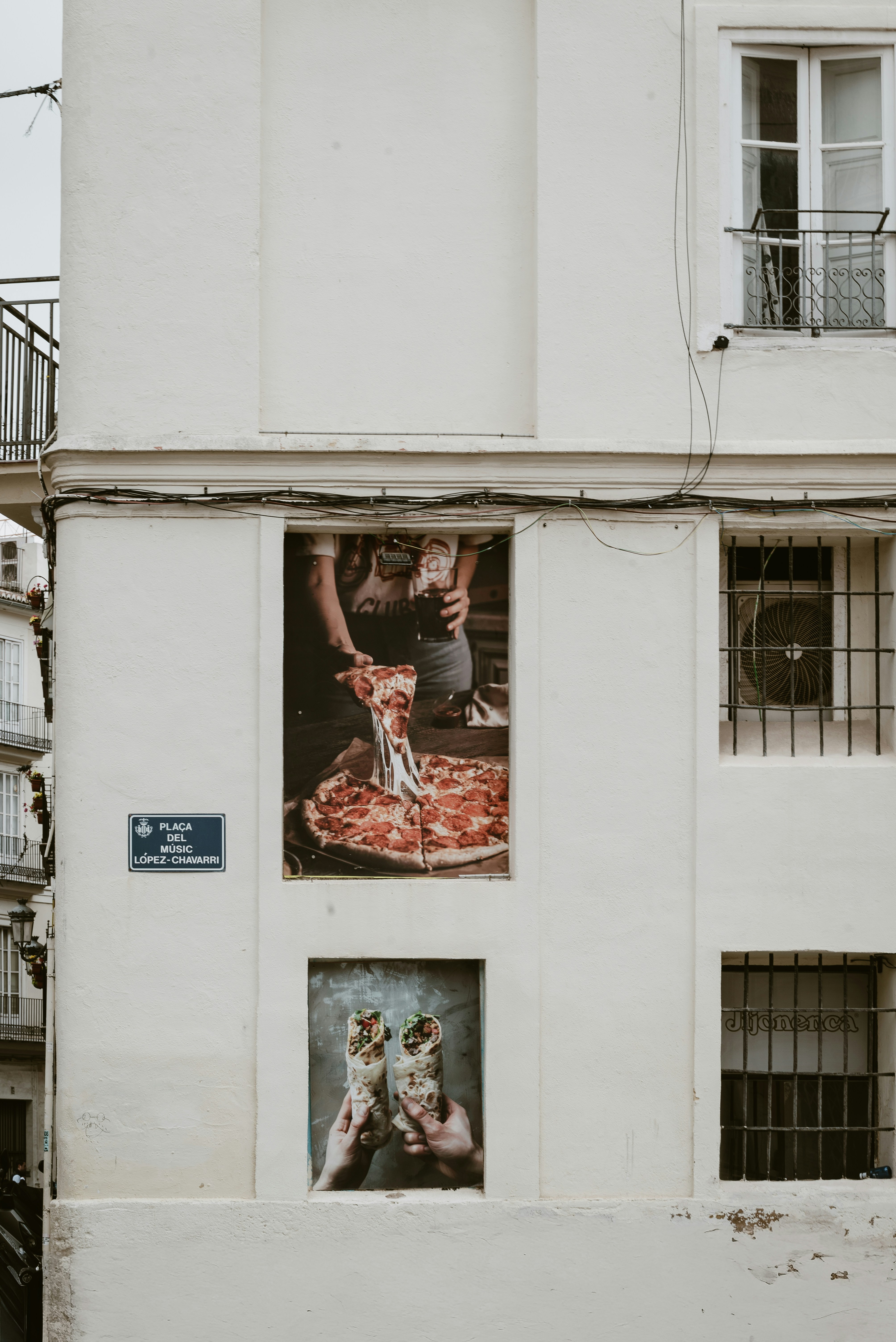 Pizza posters on a sunlit Calle Facade