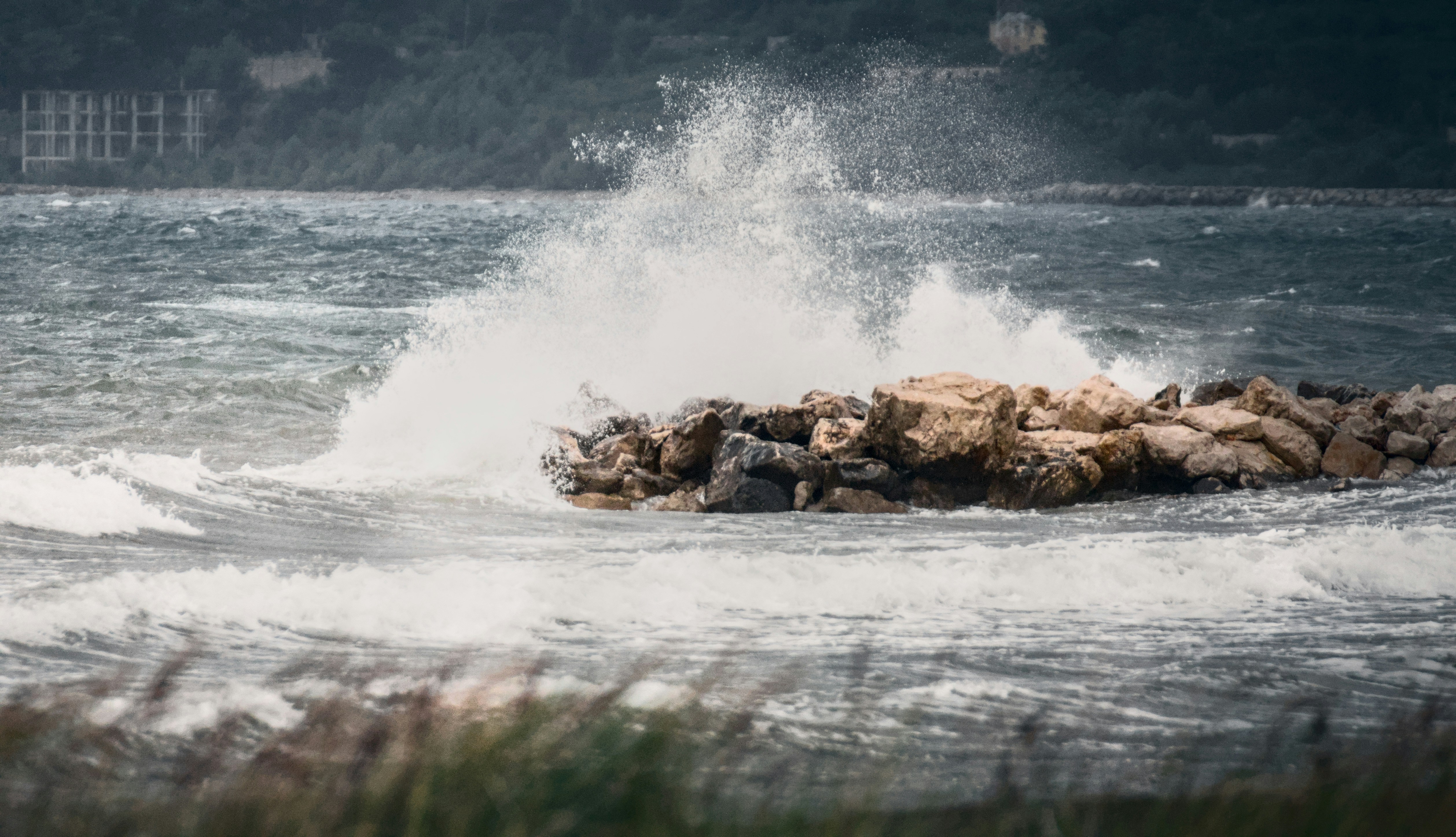 Rock Breaker: Waves Crack the Jetty Under a Distant Shoreline