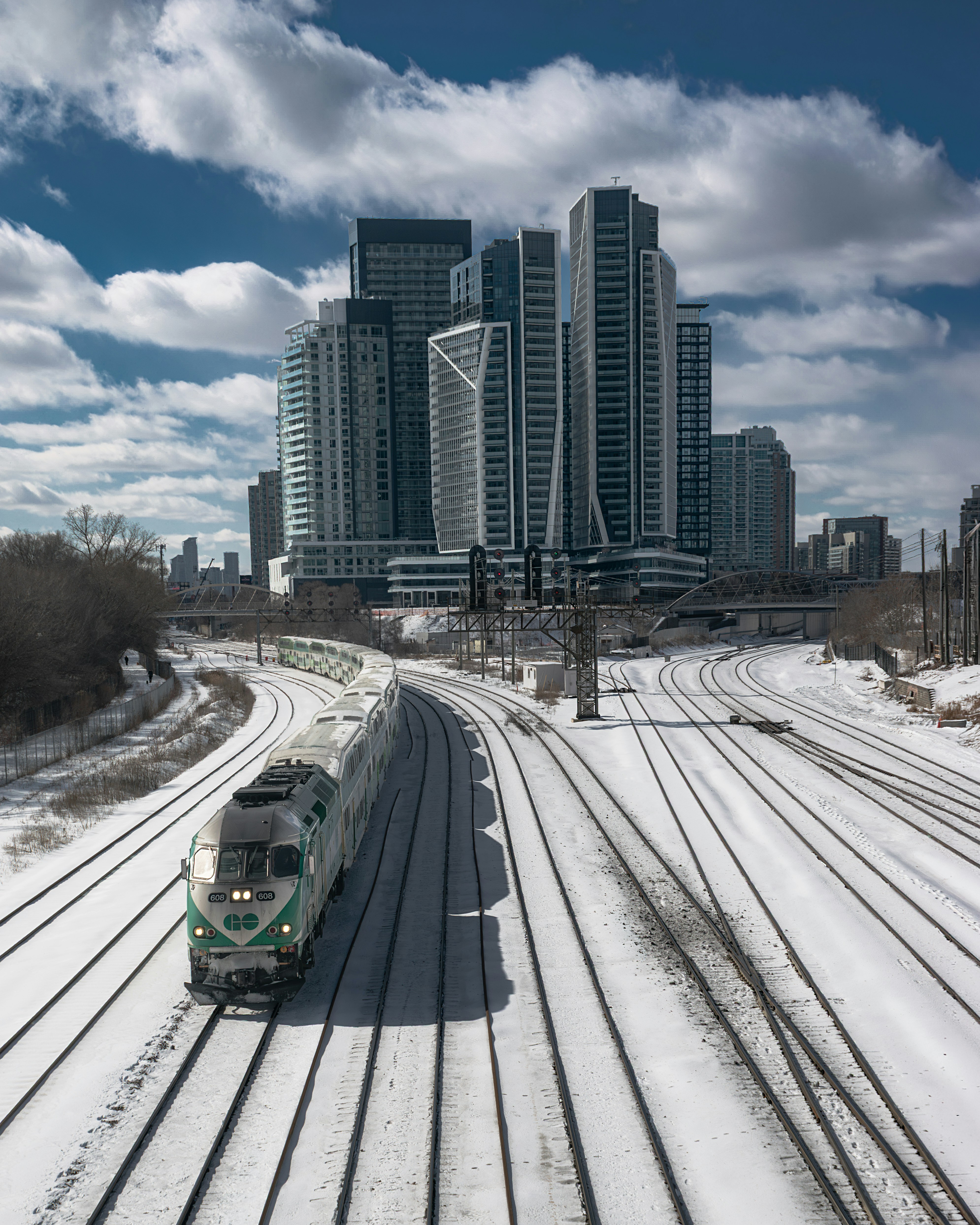 Green Locomotive Crossing Snowy Rails toward a Modern Skyline