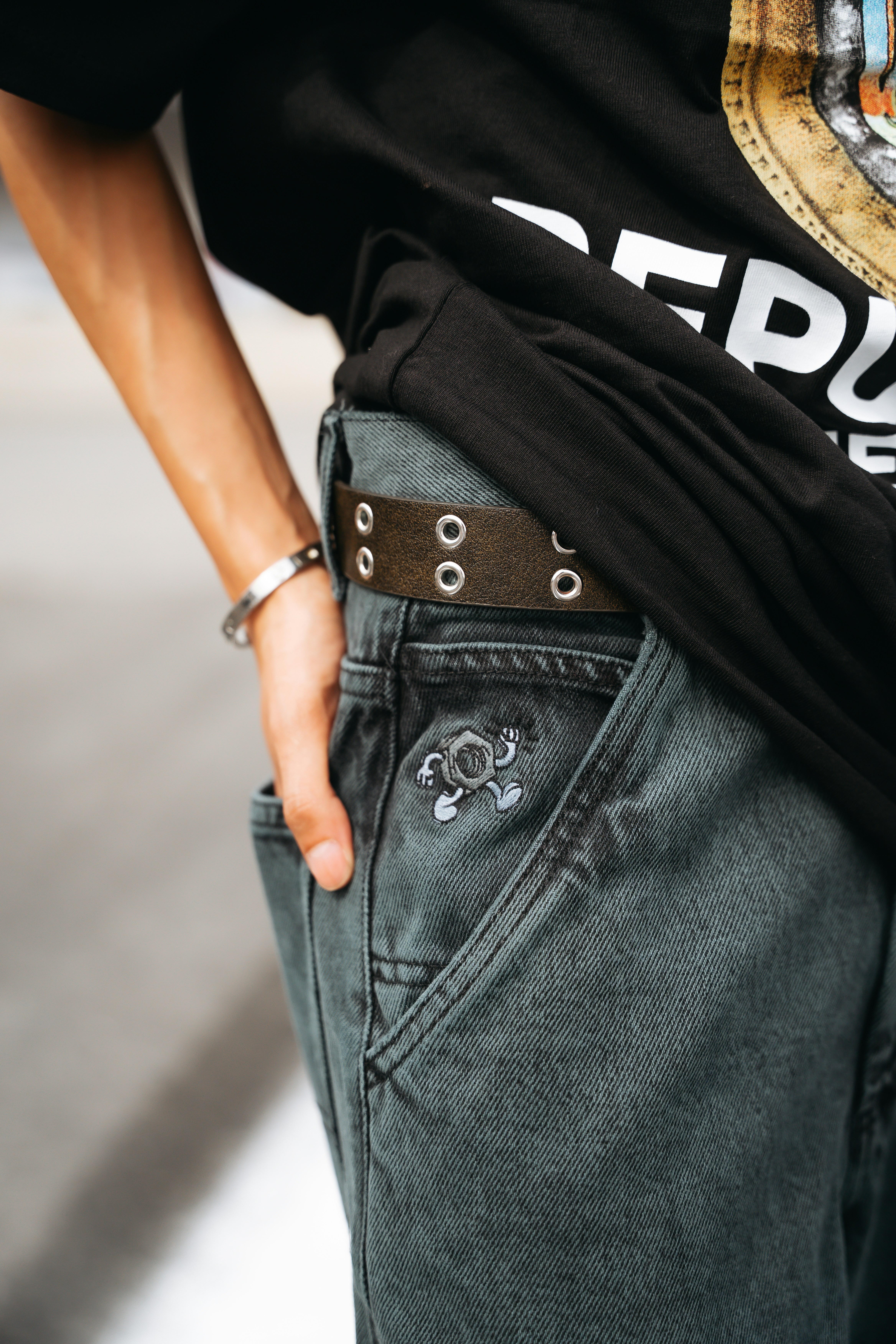 Biker’s Lean: Denim, Belt, and Bold Logo in Motion